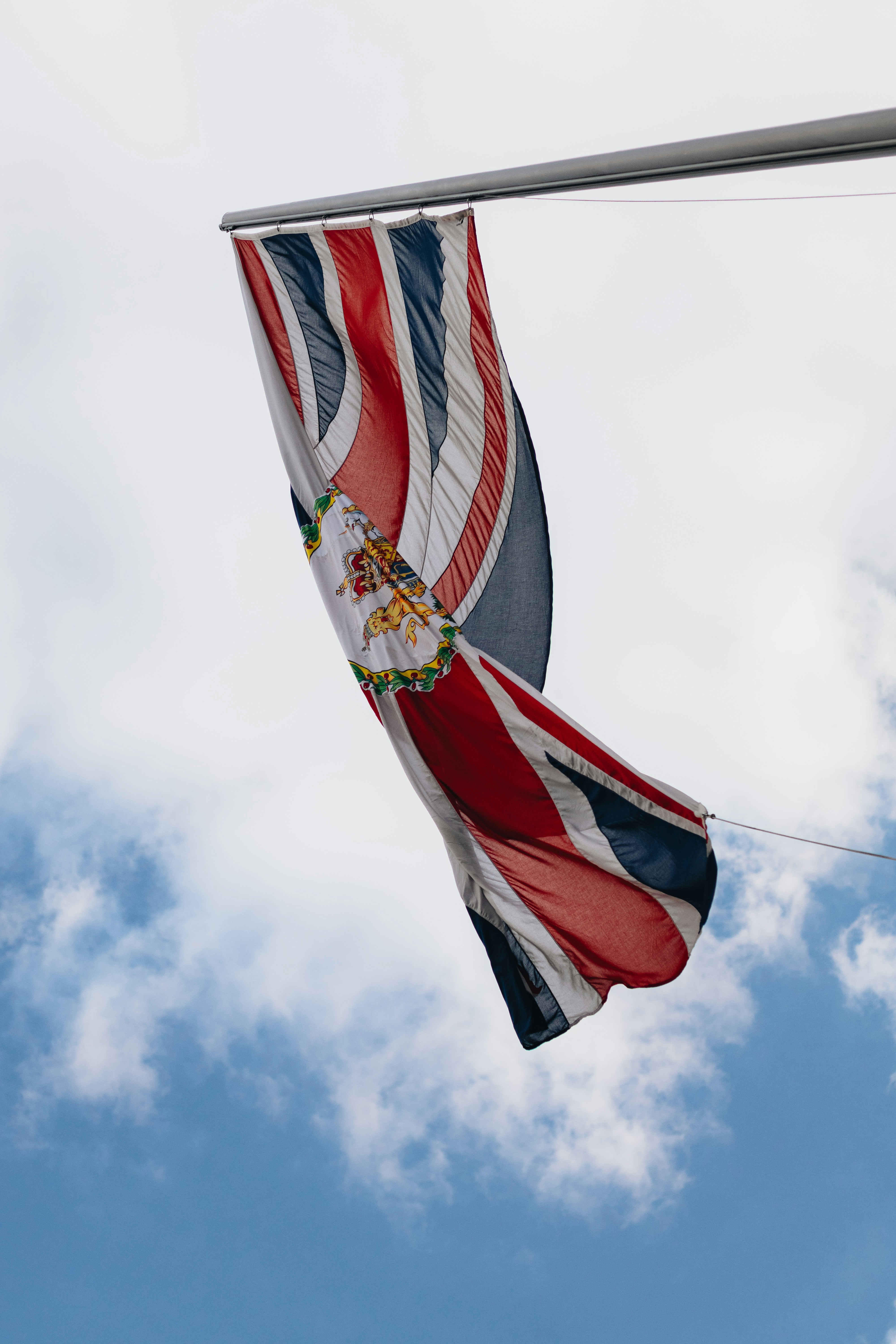 Flag in the Breeze: Union Jack and crest unfurl against a pale sky