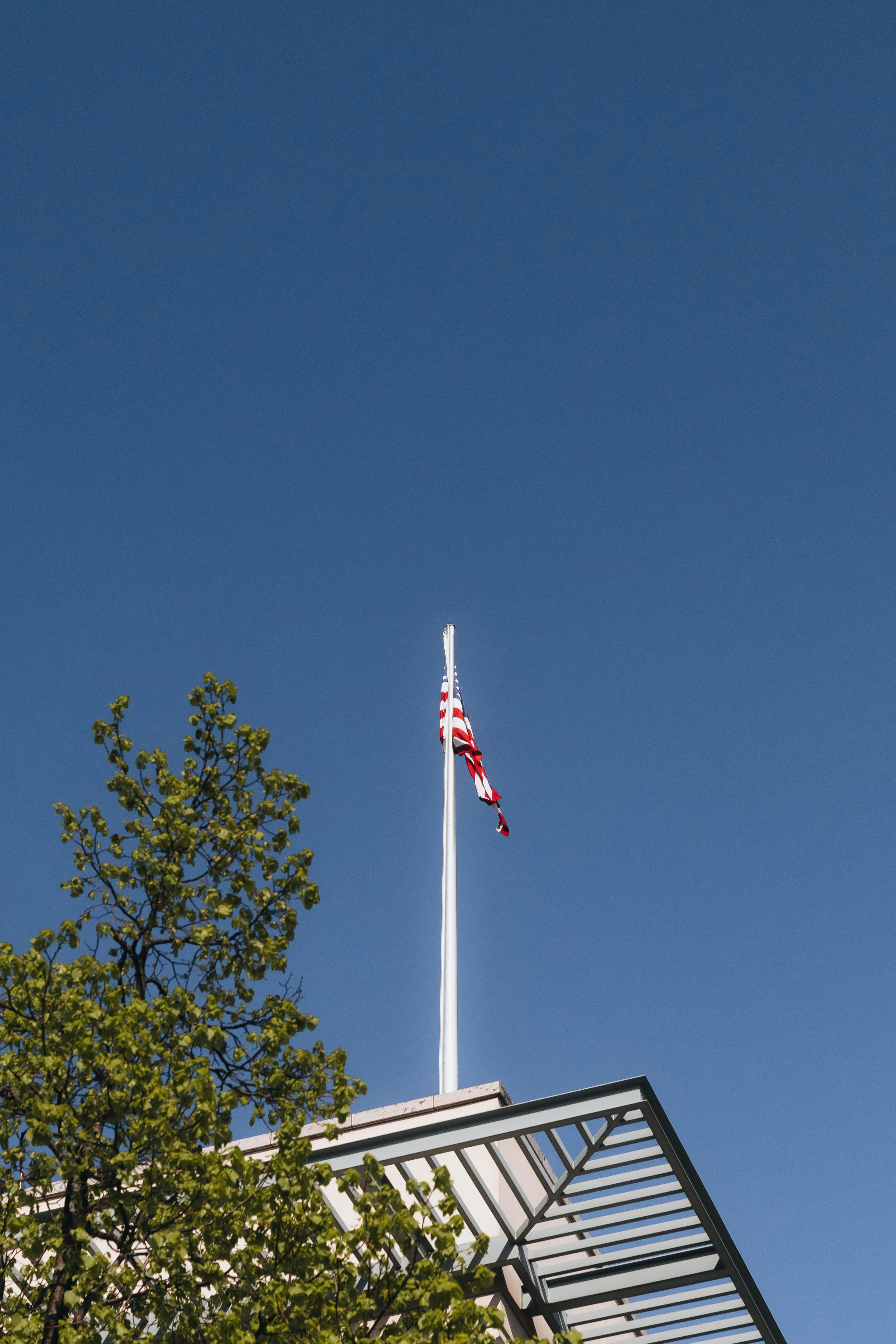 Flagpole Rising Above a Modern Roof under a Clear Blue Sky