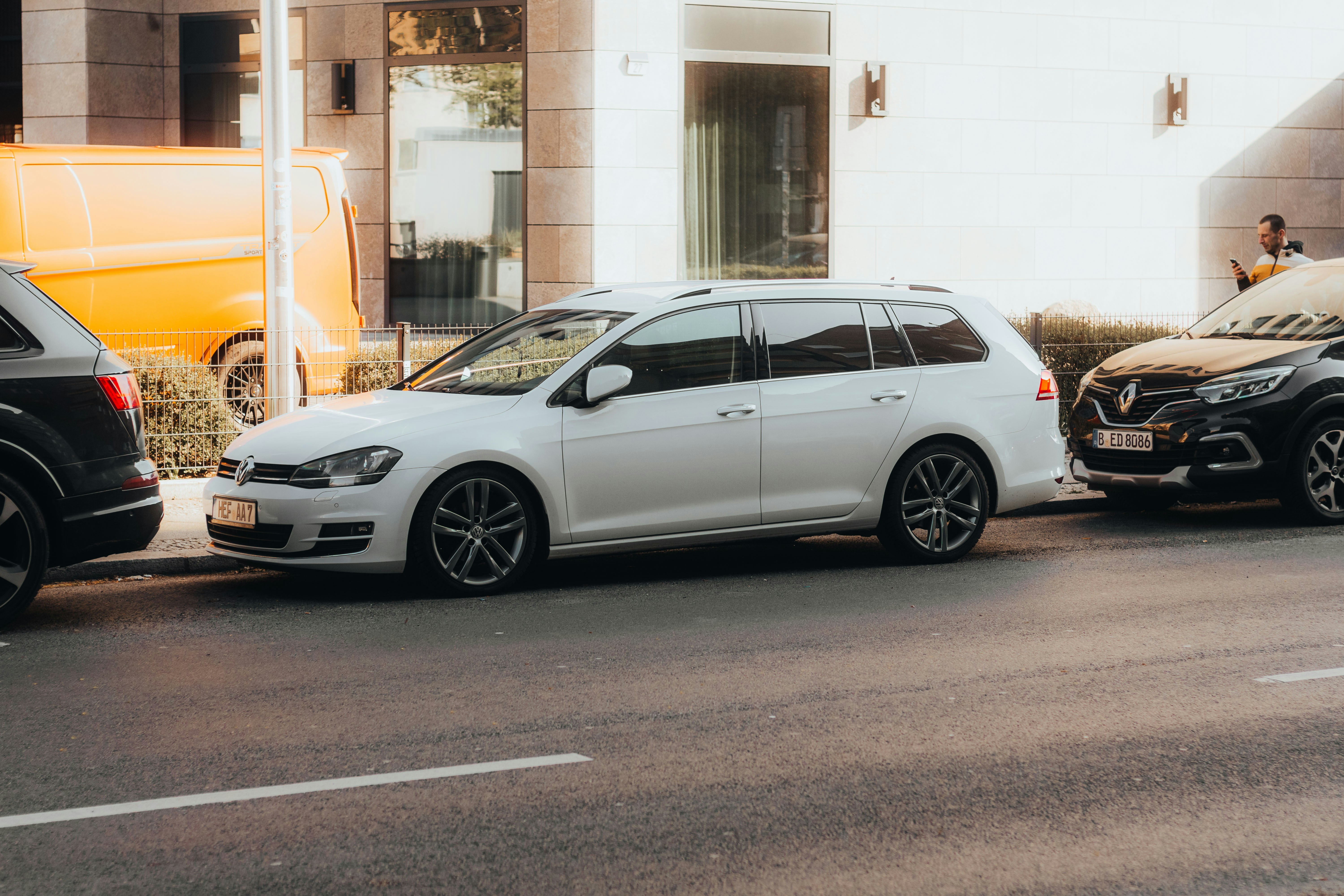 White station wagon parked along a city street with surrounding vehicles