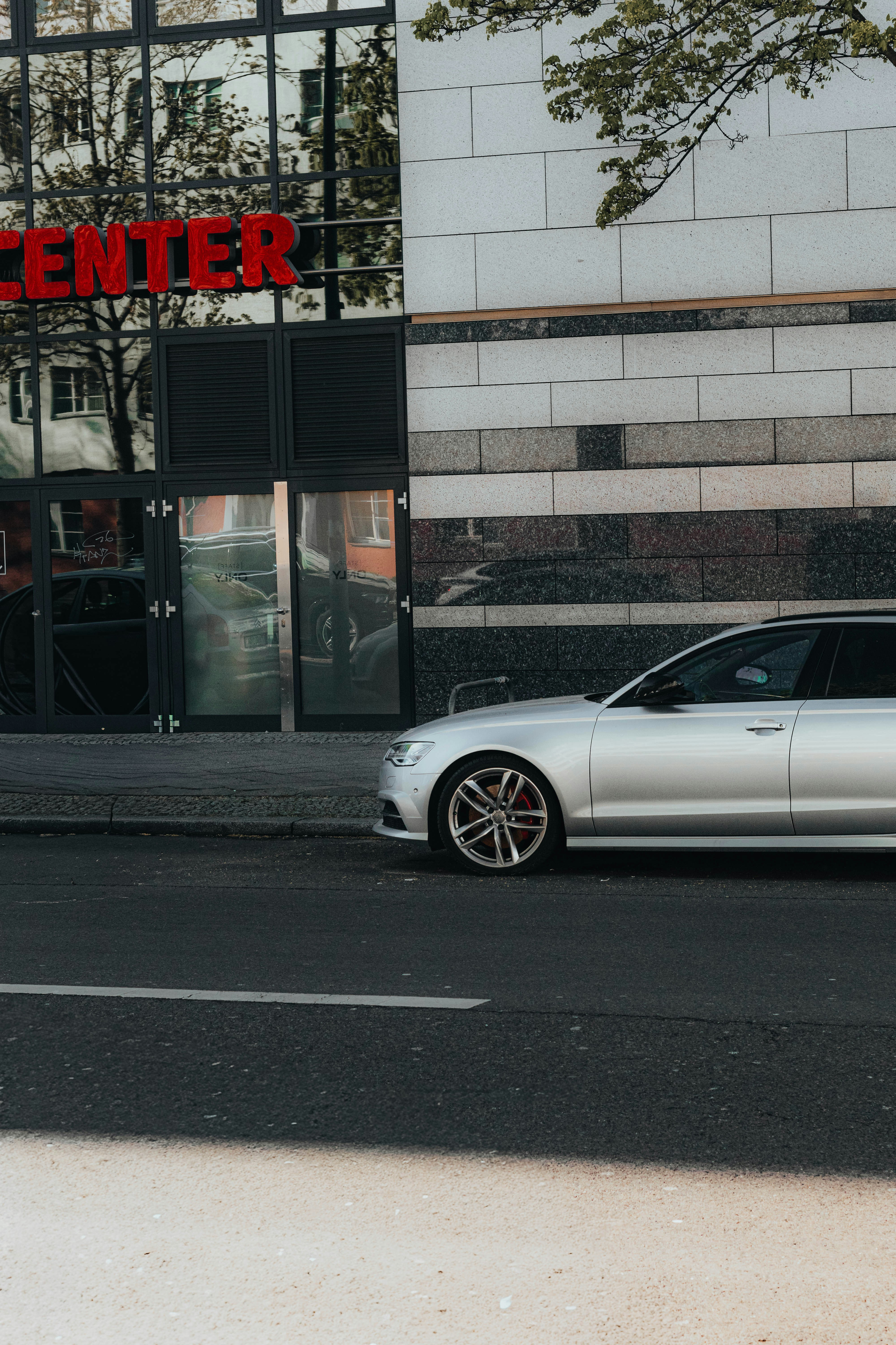 Silver sedan at the curb before a modern building with red CENTER sign