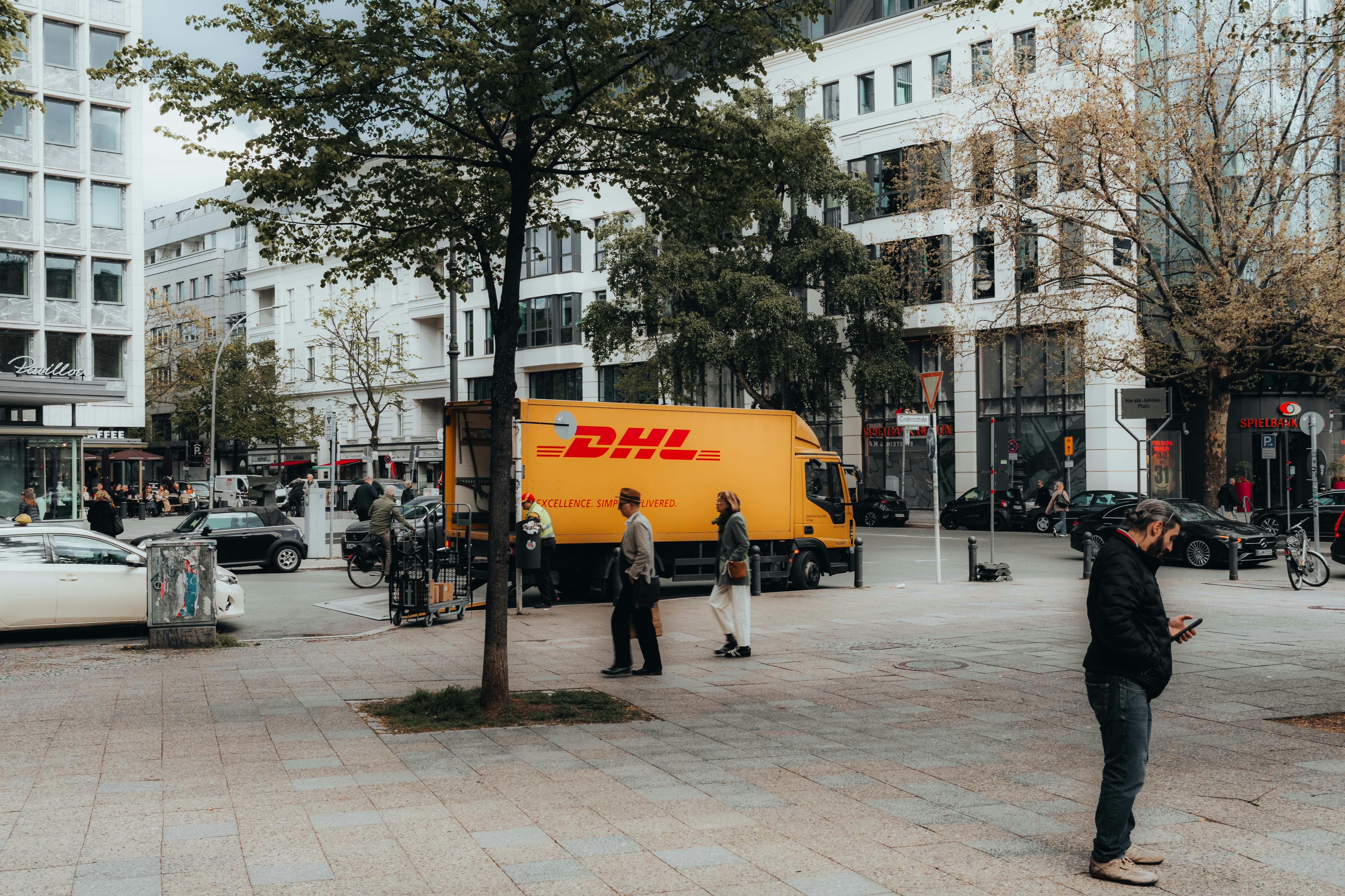 A yellow dhl truck parked on a city street.