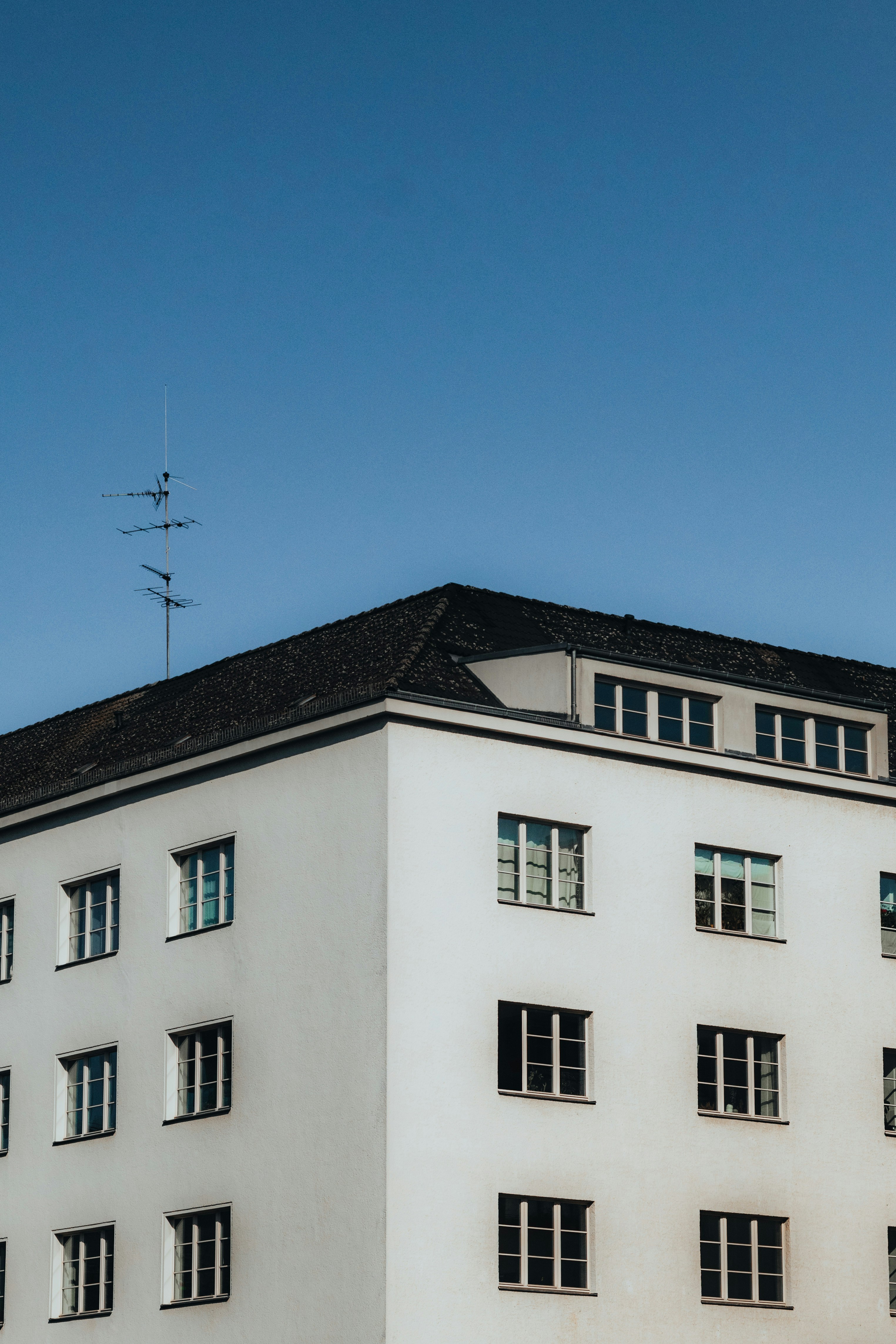 Cornered Skyline: A Quiet Rooftop Portrait Against a Clear Blue