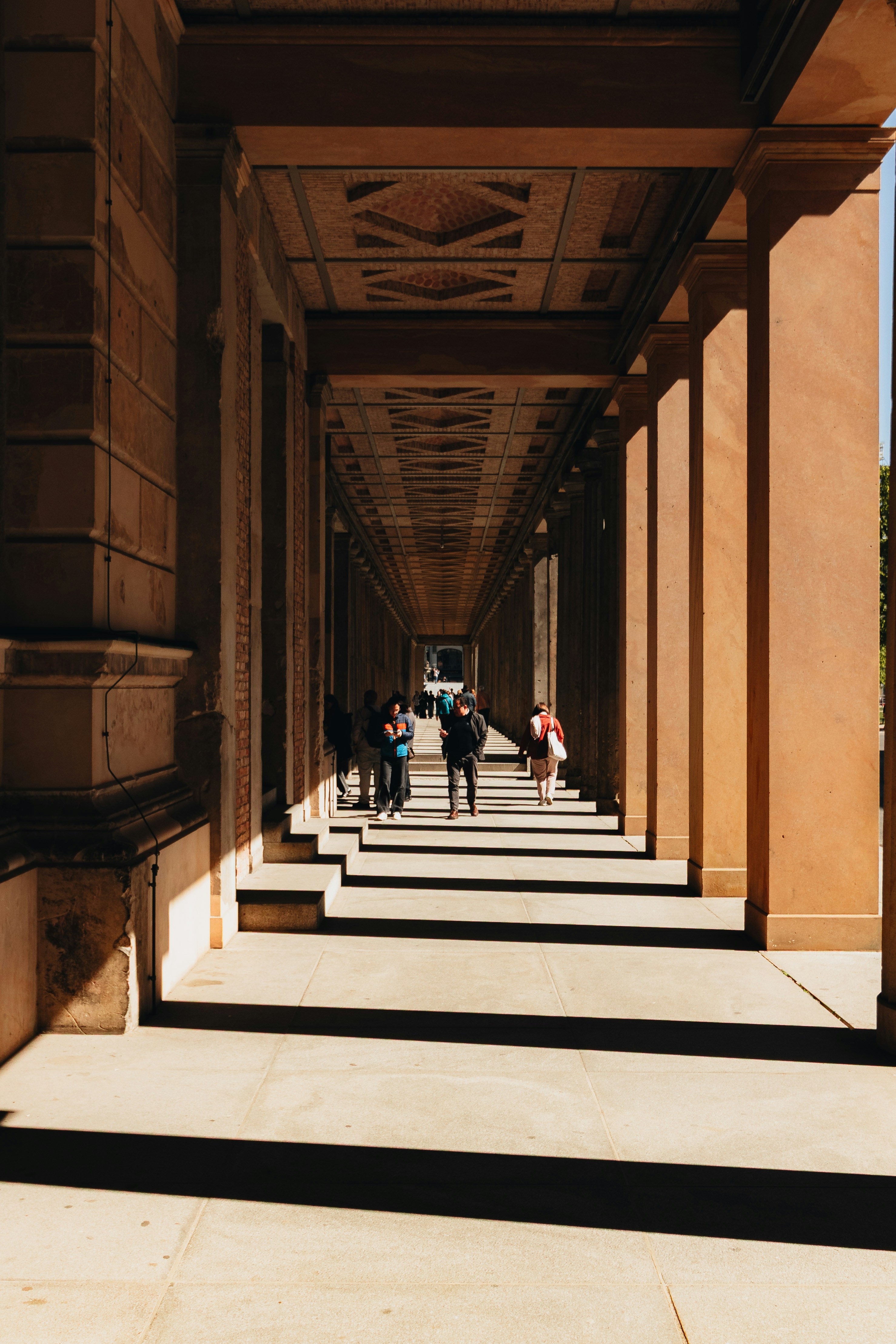 Colonnade Convergence: People Walking Toward the Distant Light
