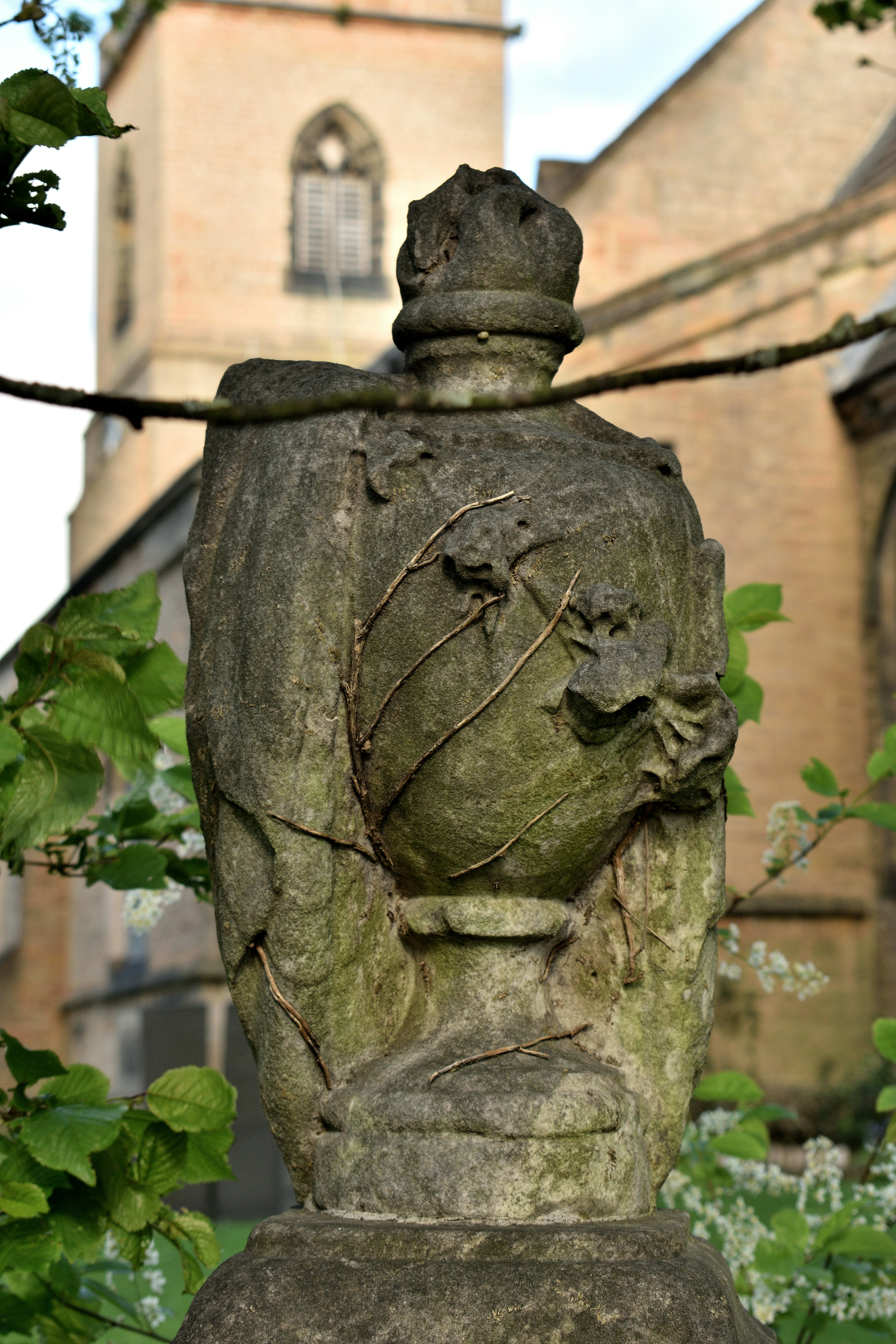 Weathered statue amid ivy with Gothic architecture backdrop
