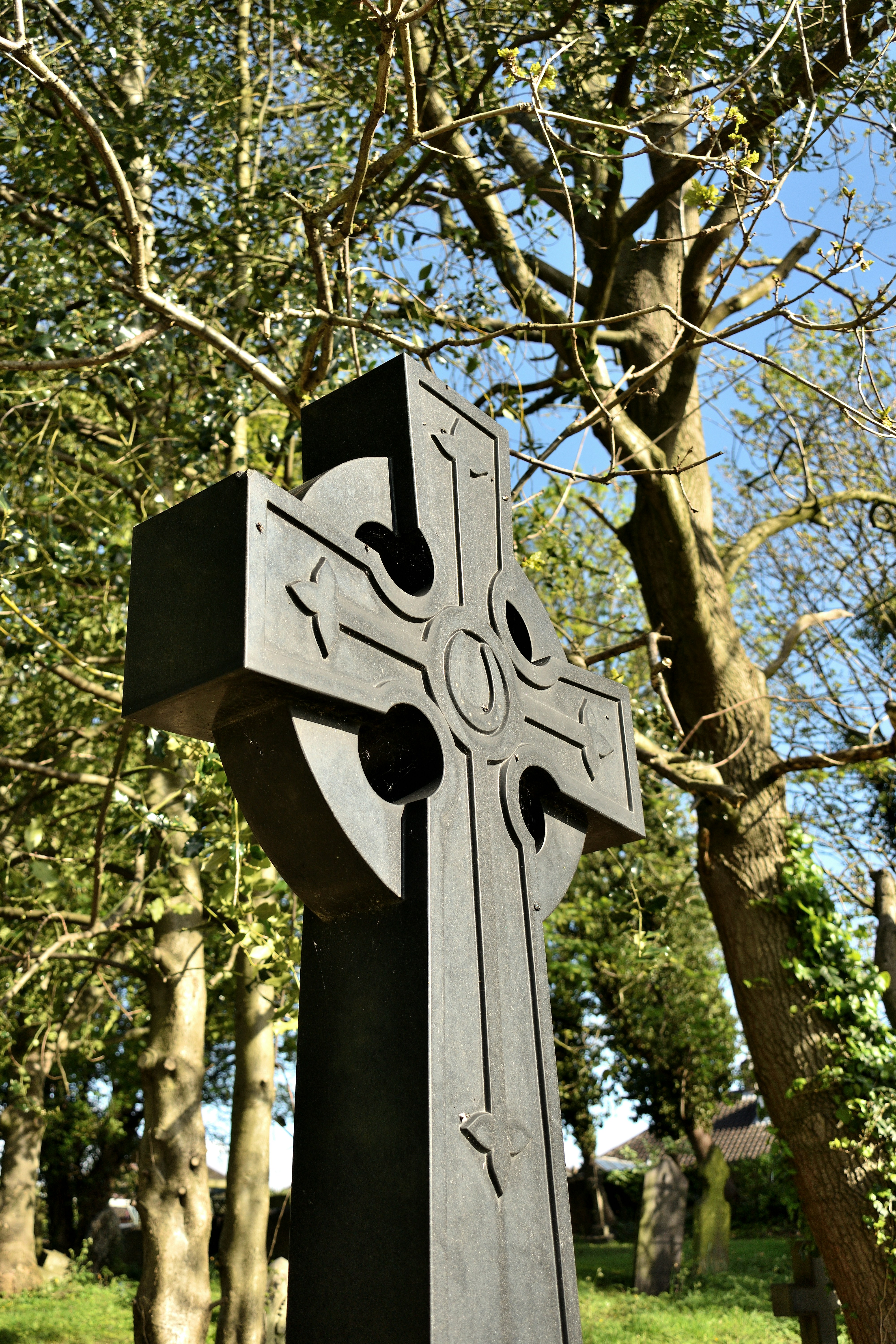Cross in the Garden: A Quiet Monument Against Sunlit Trees