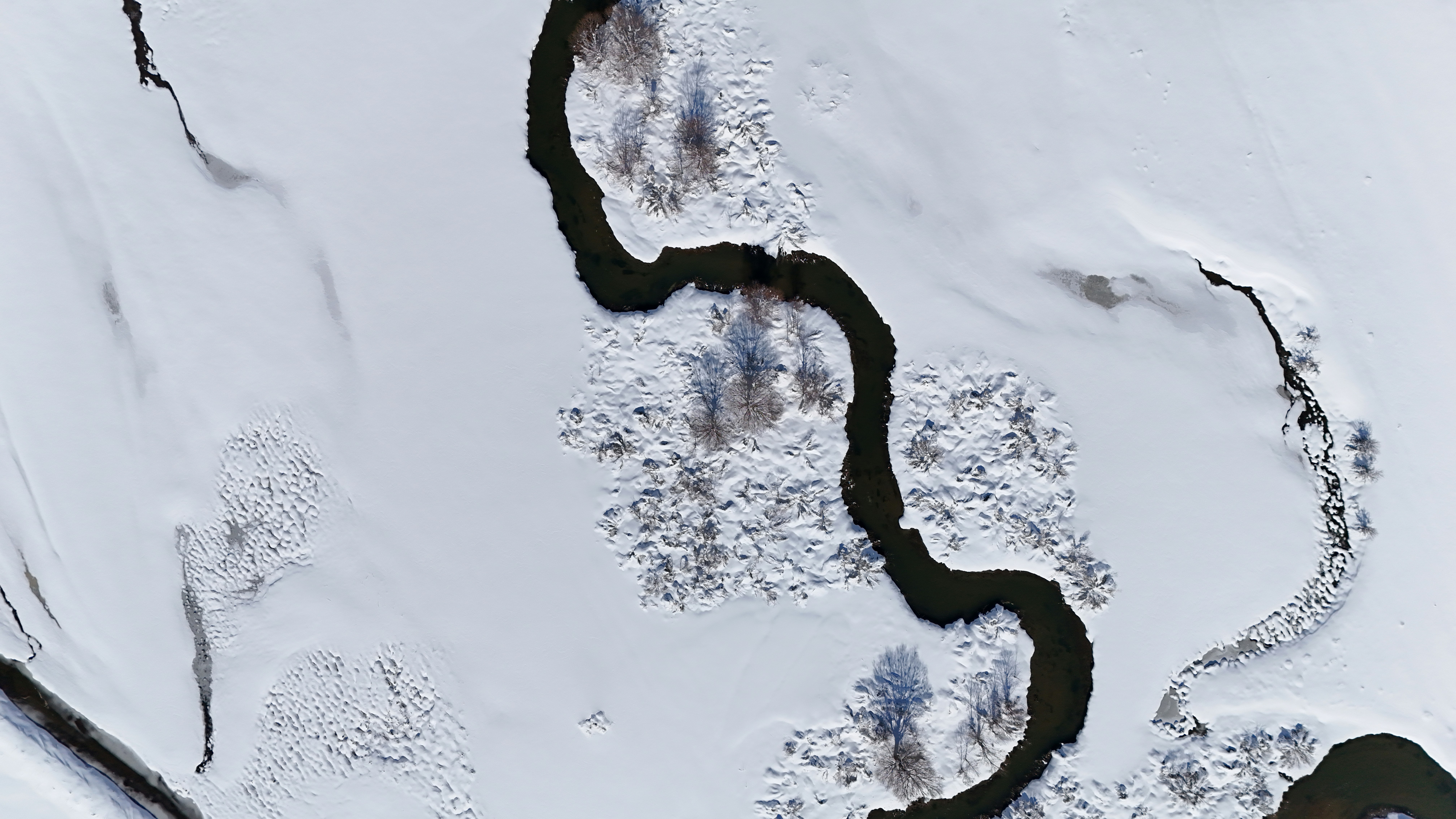 Snowbound S-Curve: A Quiet Cold Channel Winding Through White Terrain