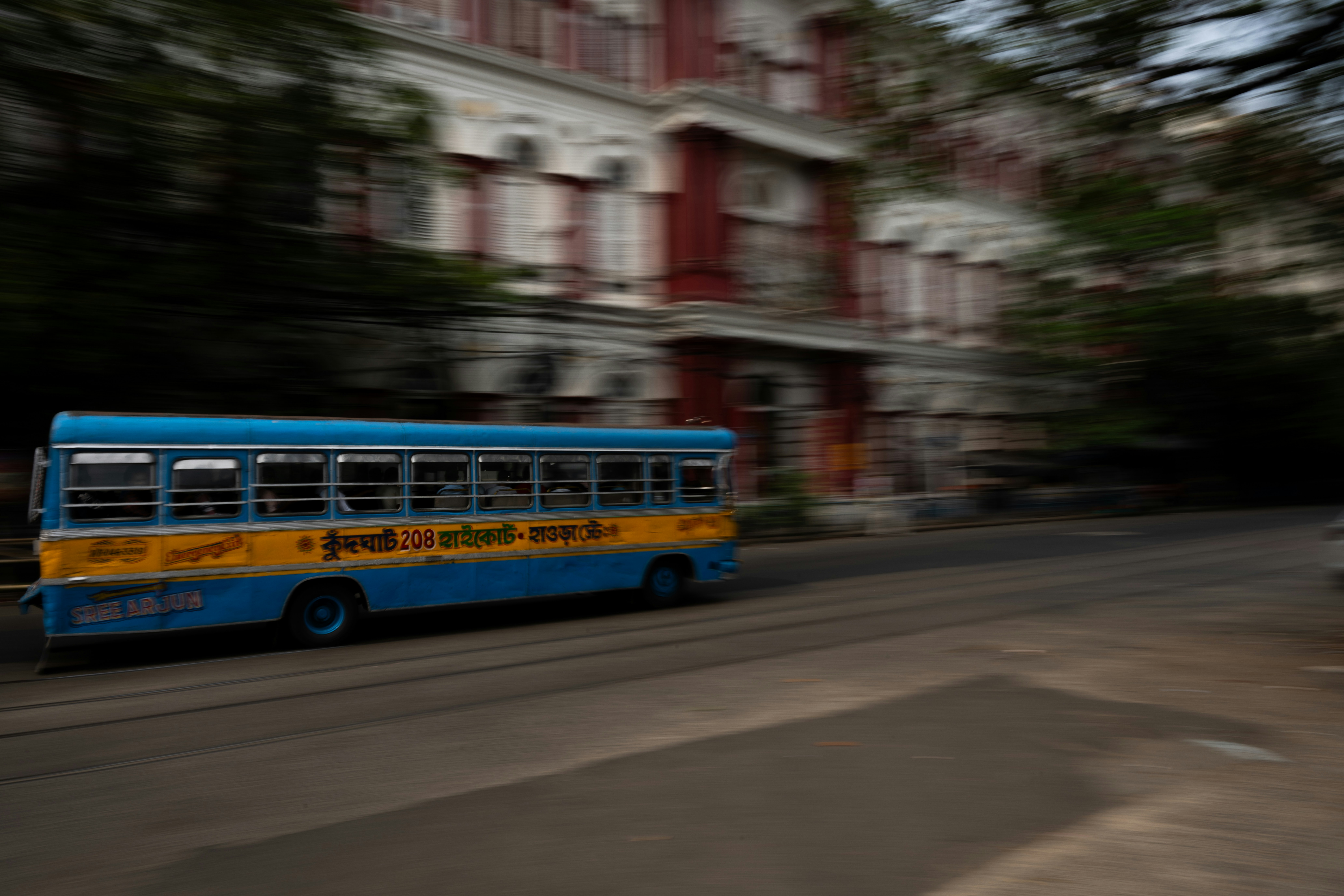 Blue bus in motion along a sunlit city street