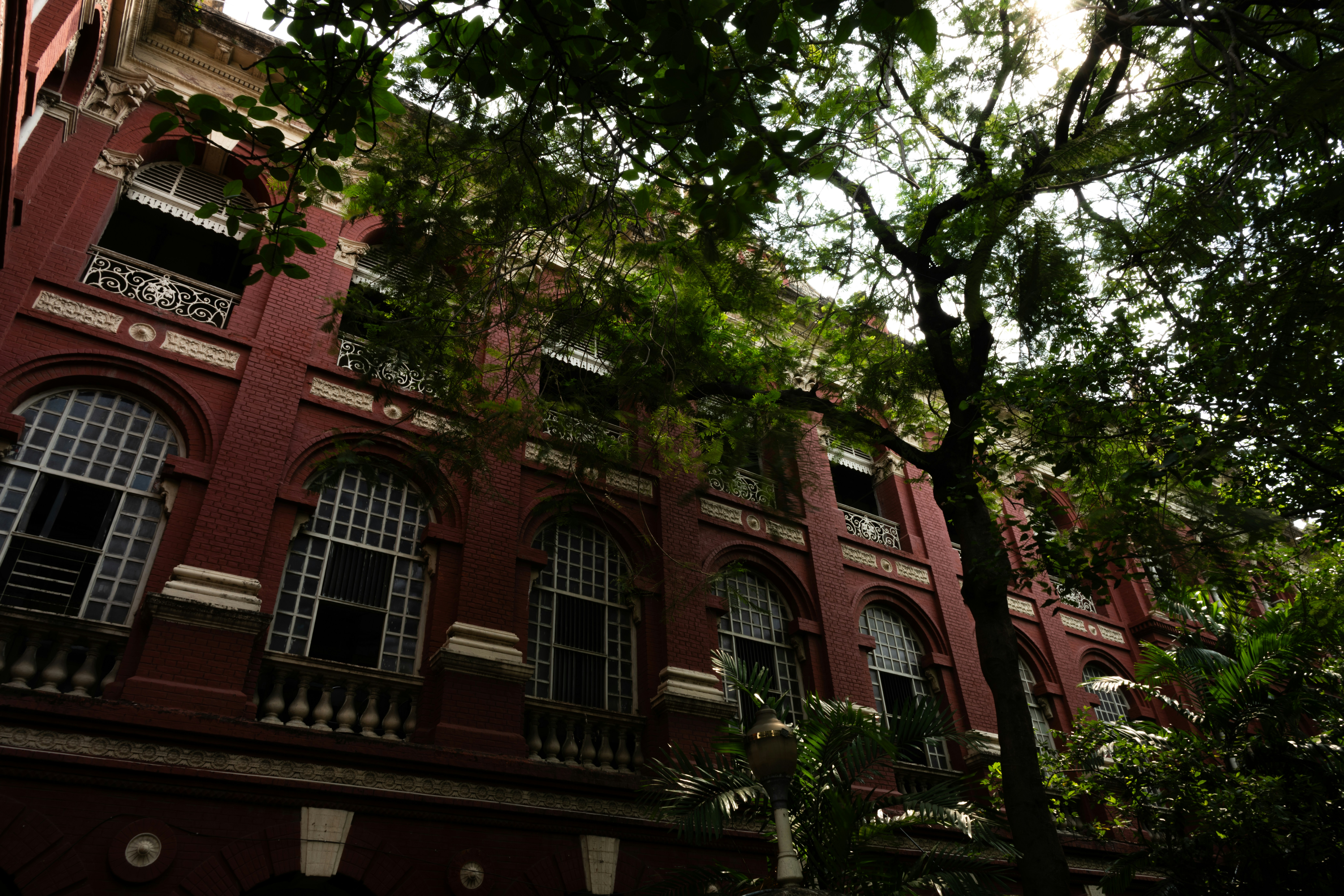 Historic red building with ornate windows and trees