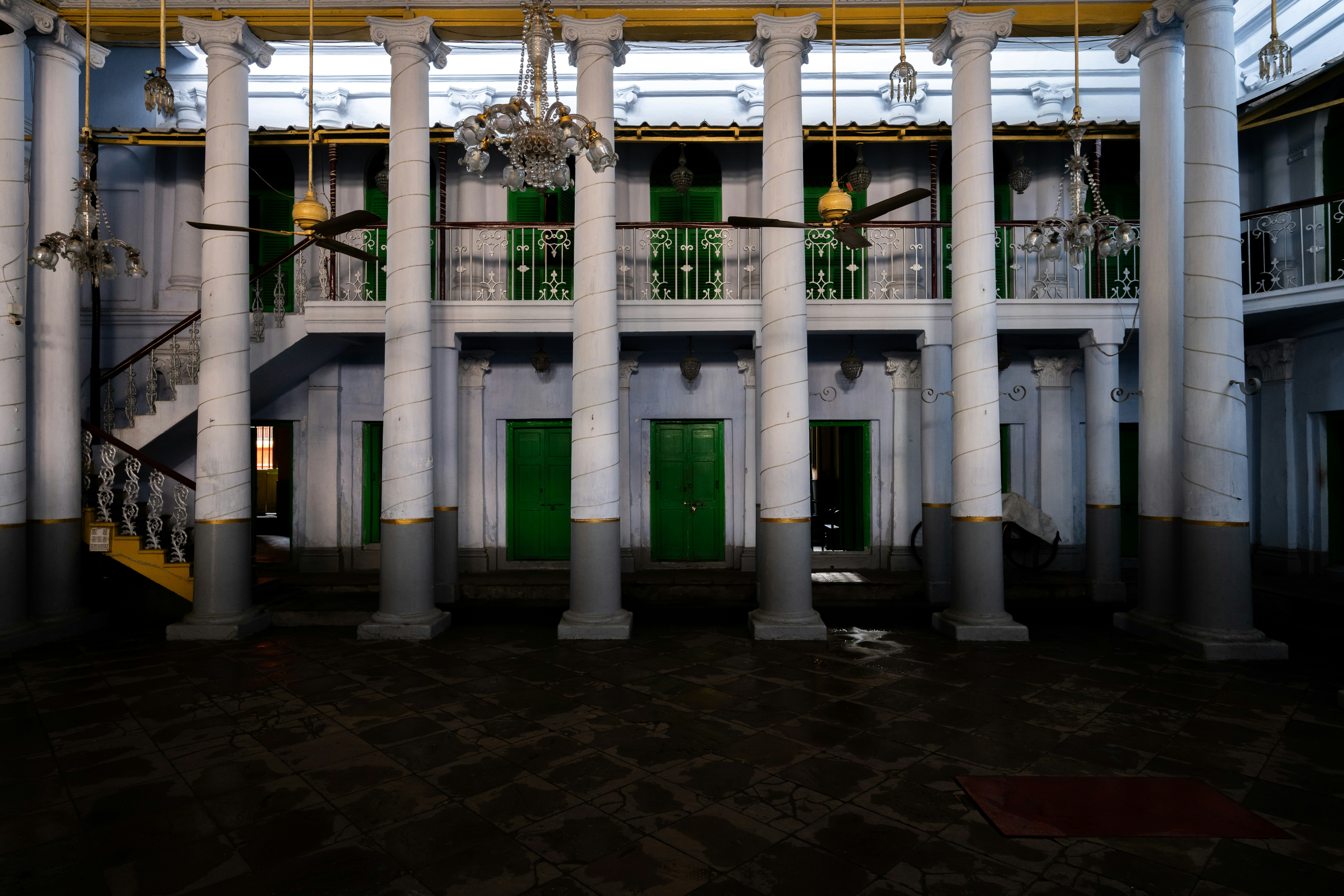 Centered Hall of Columns: Green Doors in a Dim Courtyard