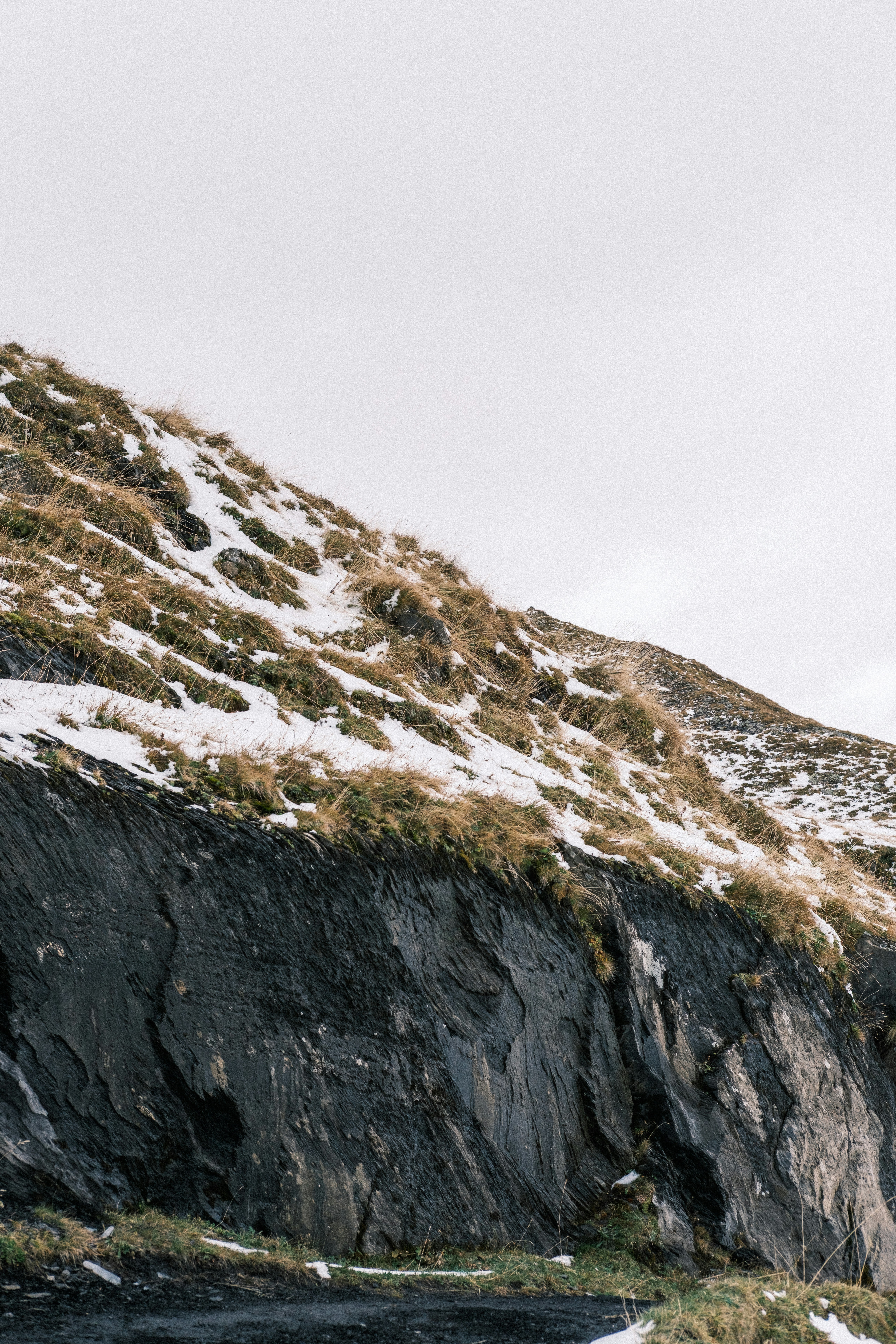 Snow-kissed cliff edge under a pale sky