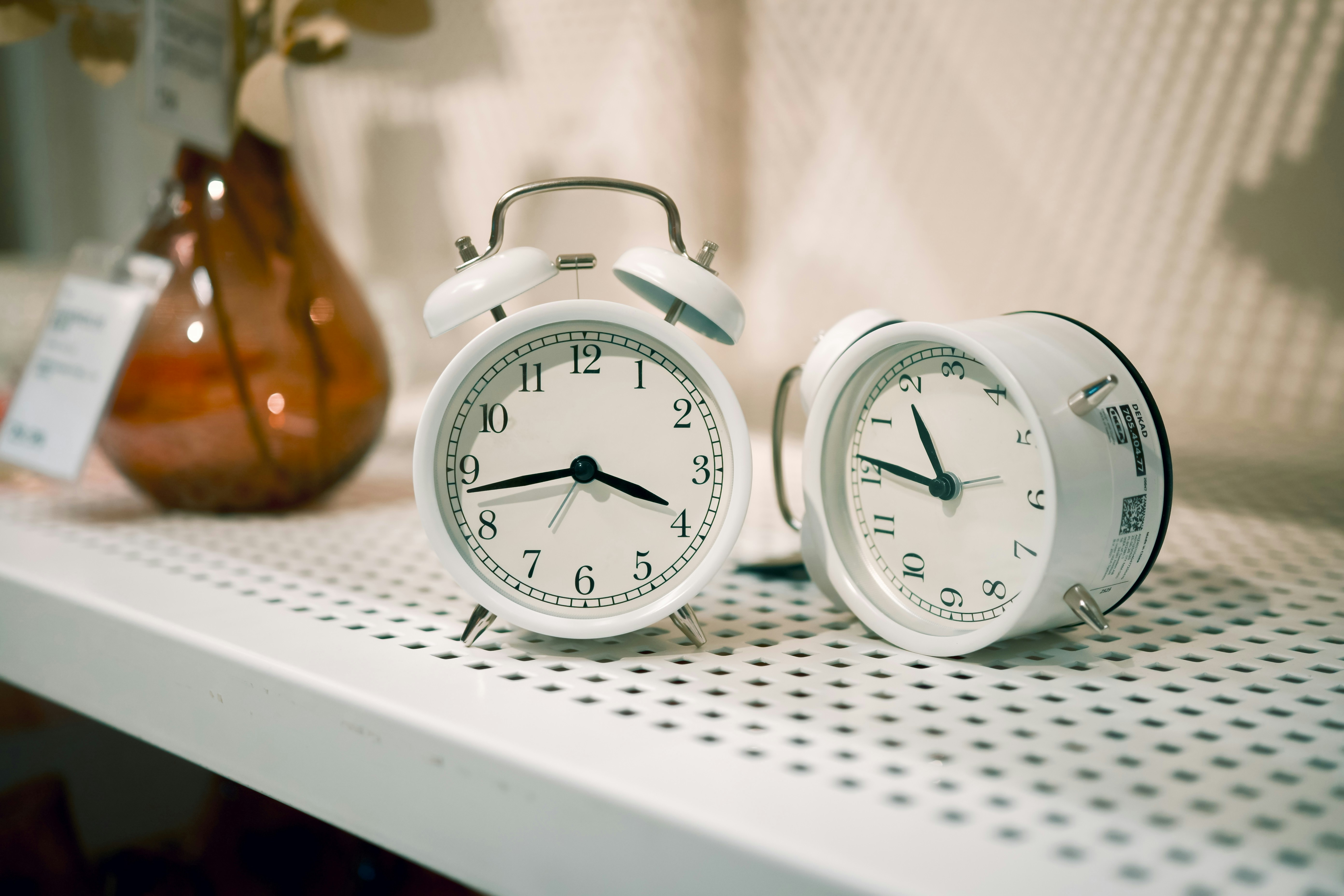 Twin White Alarm Clocks on a Perforated Shelf