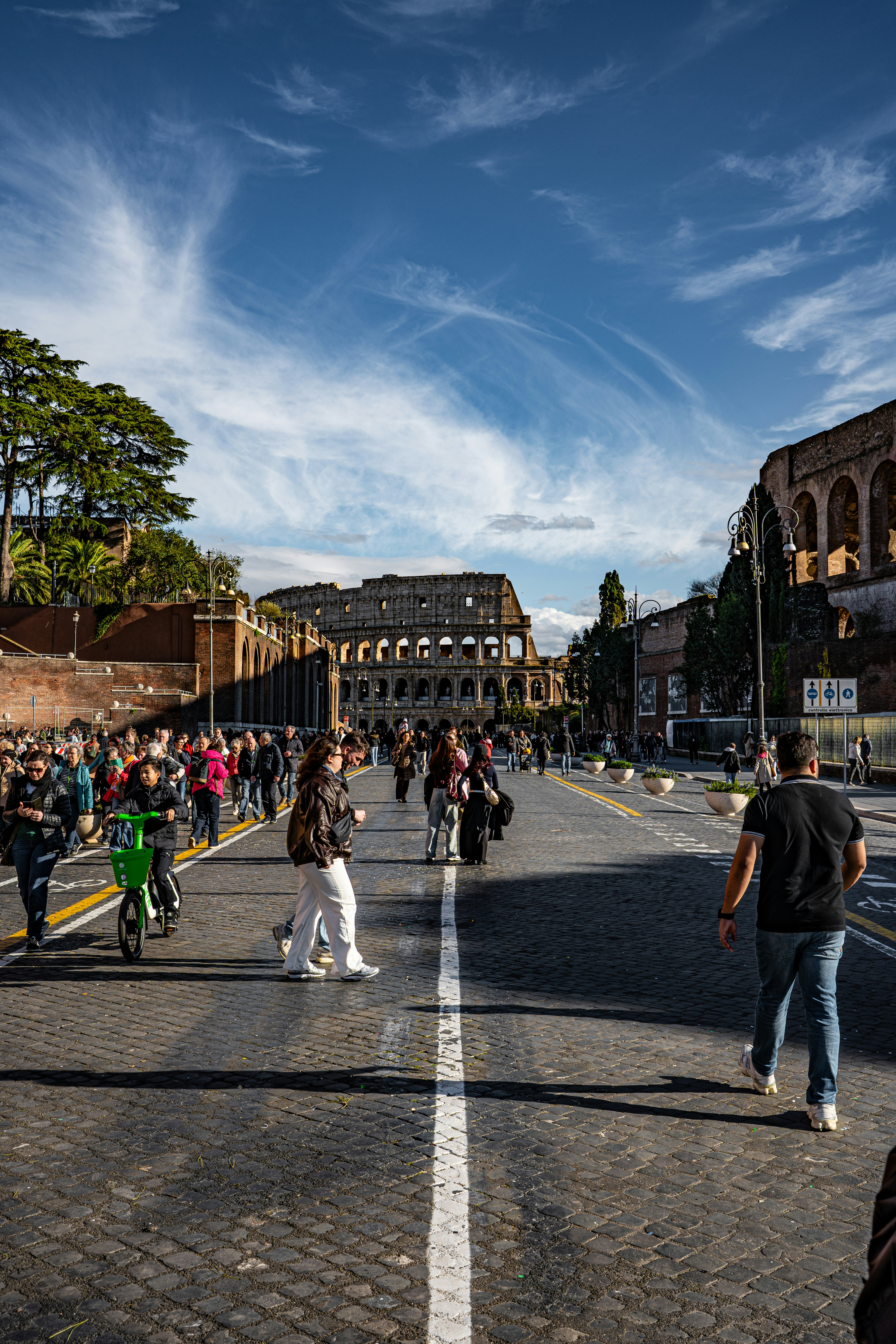 Crucial Route: Tourists and the Colosseum-like Ruins Under a Wide Blue Sky