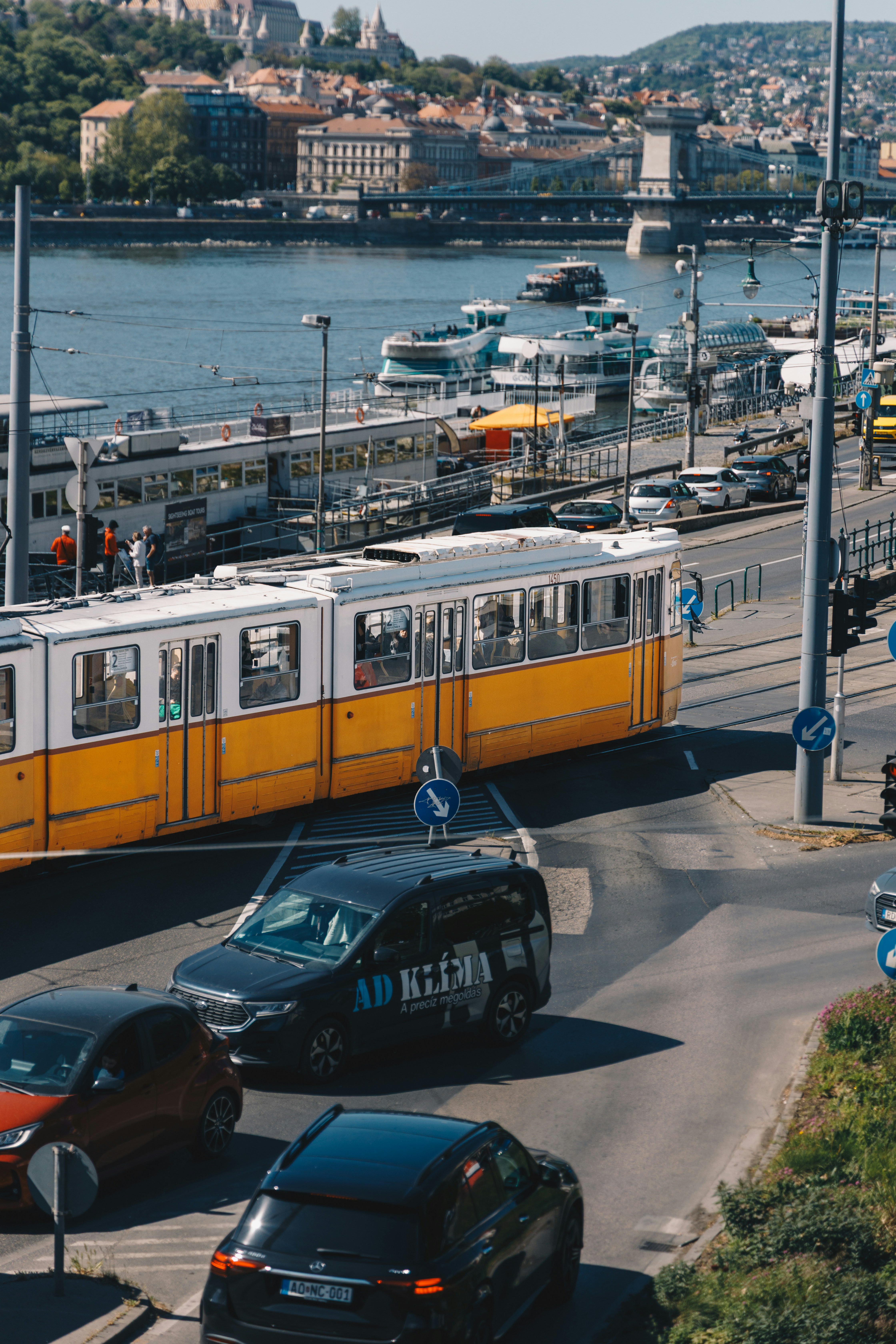 Yellow tram slicing through morning riverfront traffic
