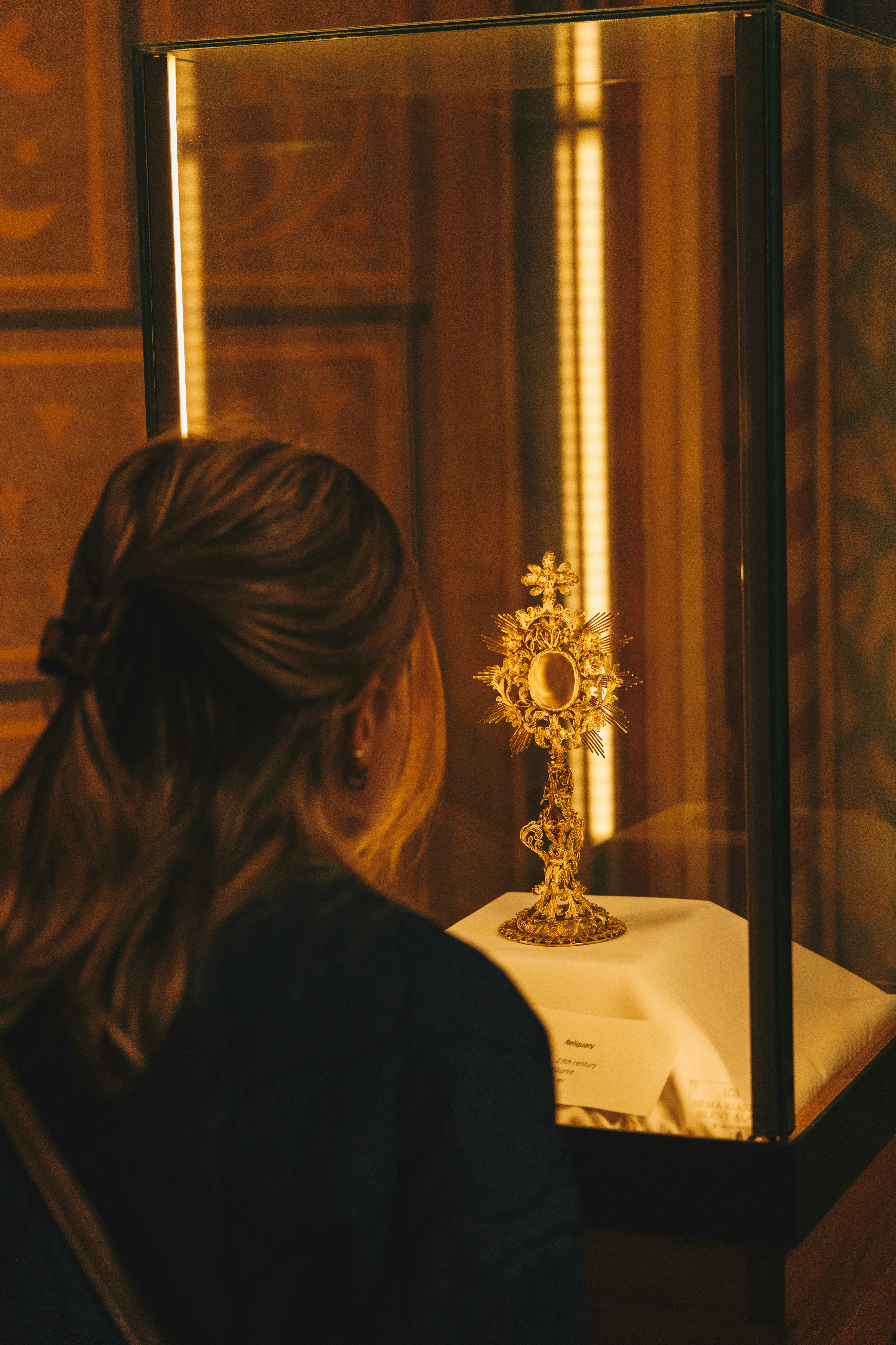Whispered Reverence: A Visitor Faces a Golden Monstrance