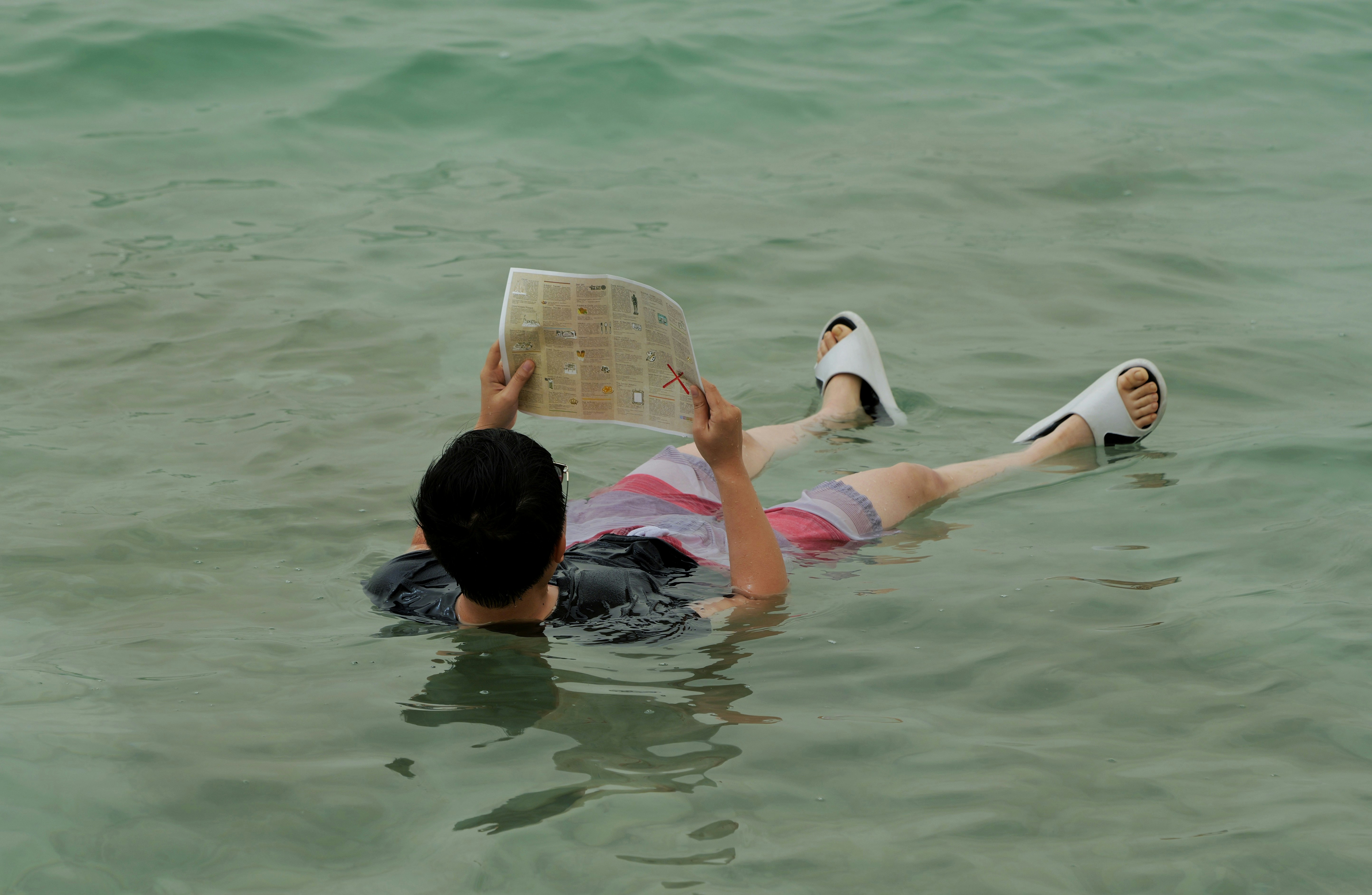 Quiet Float: A Reader Drifts with a Map on Sunlit Calm