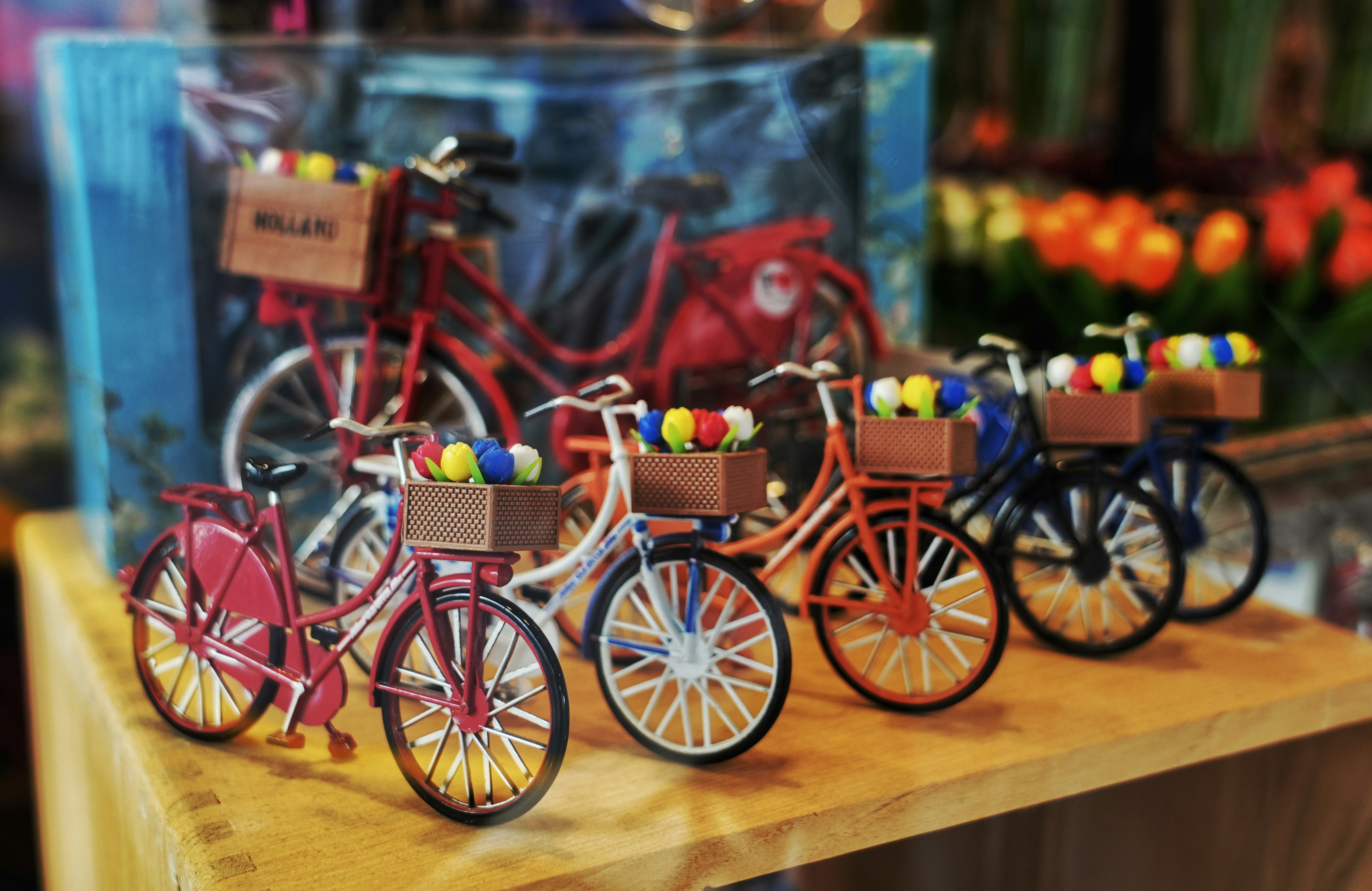 Row of toy bicycles with colorful baskets and flowers on a wooden surface