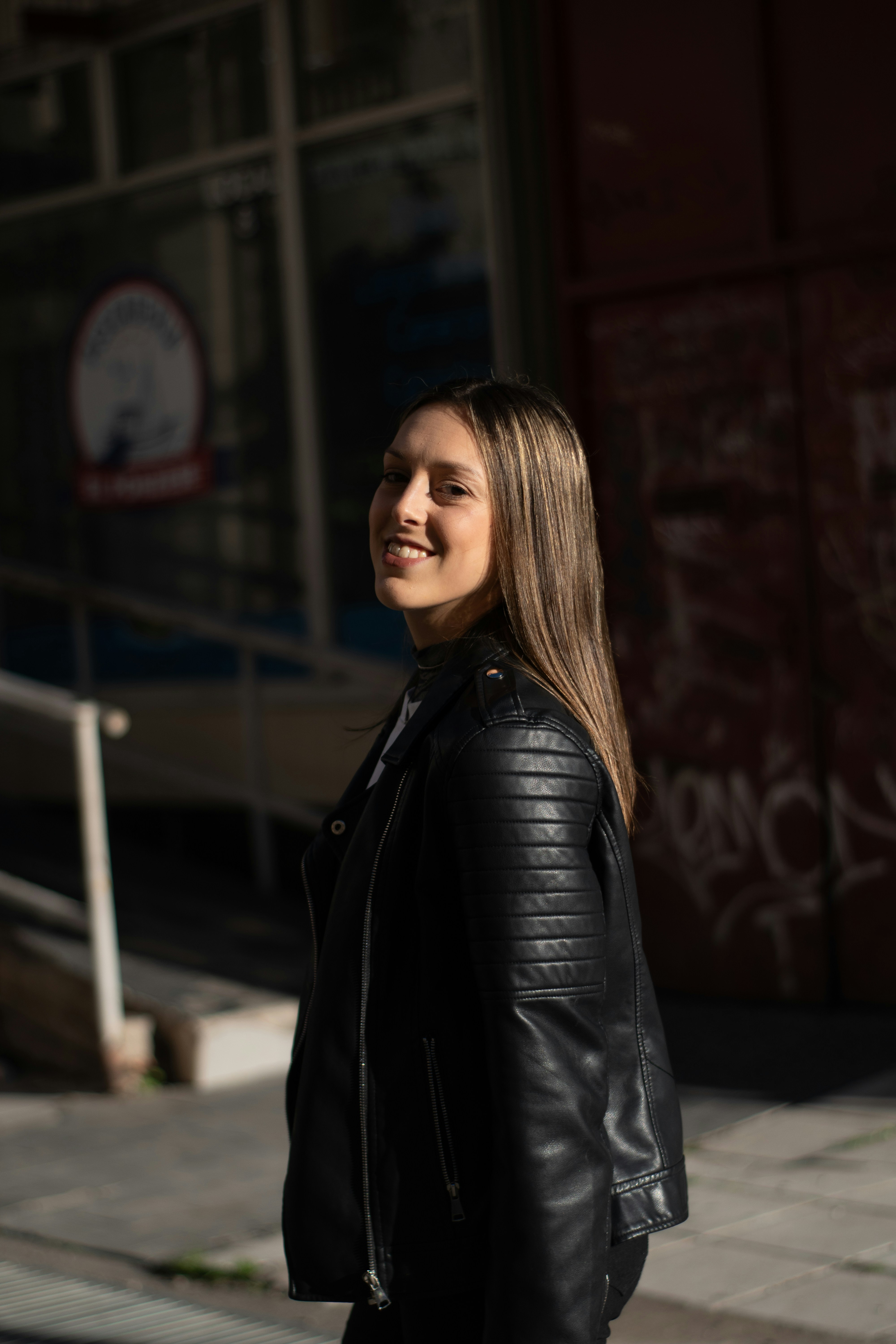 Sunlit Smile: A Leather-Clad Portrait in Urban Light