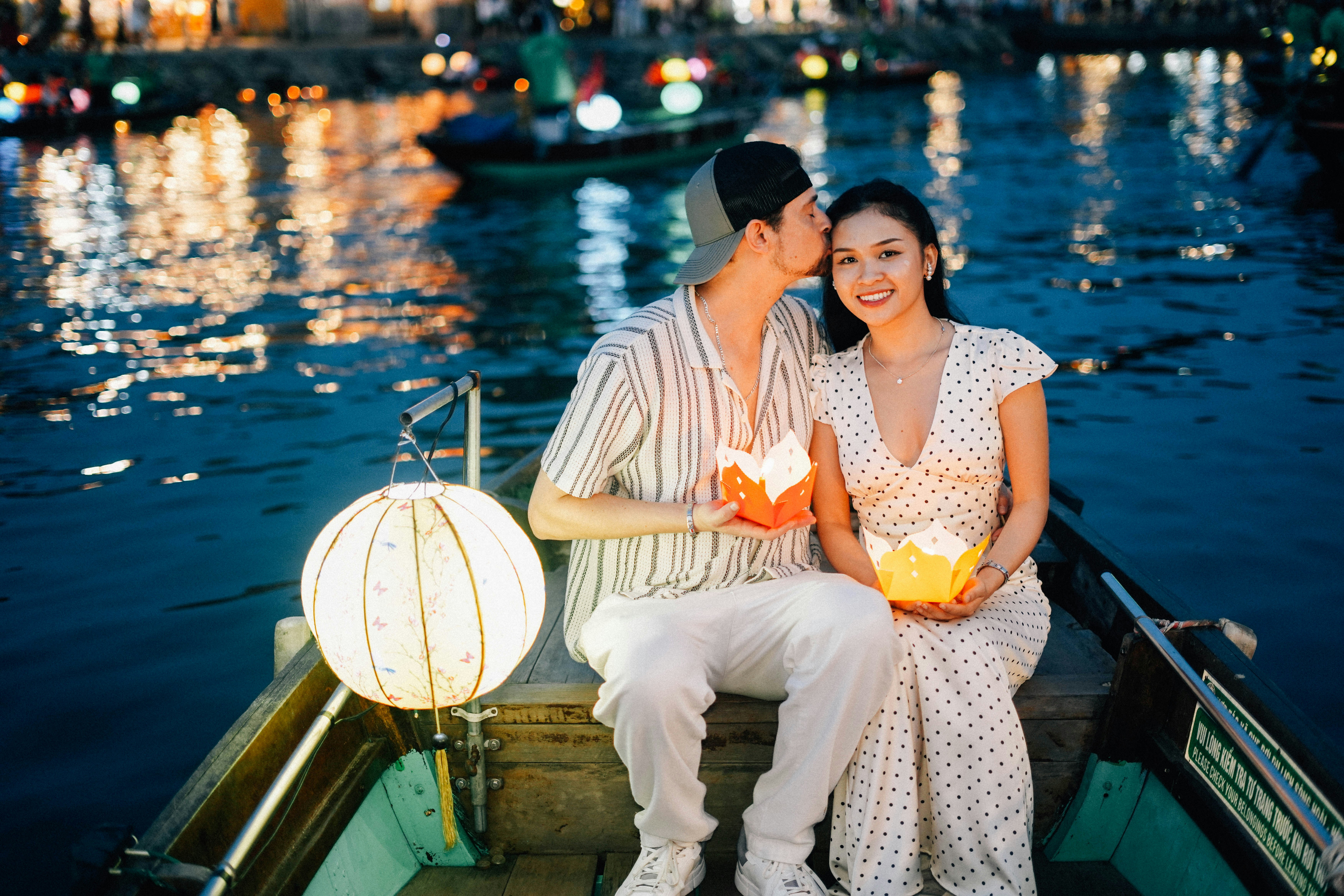 Candlelit couple sharing a kiss in a moonlit riverboat