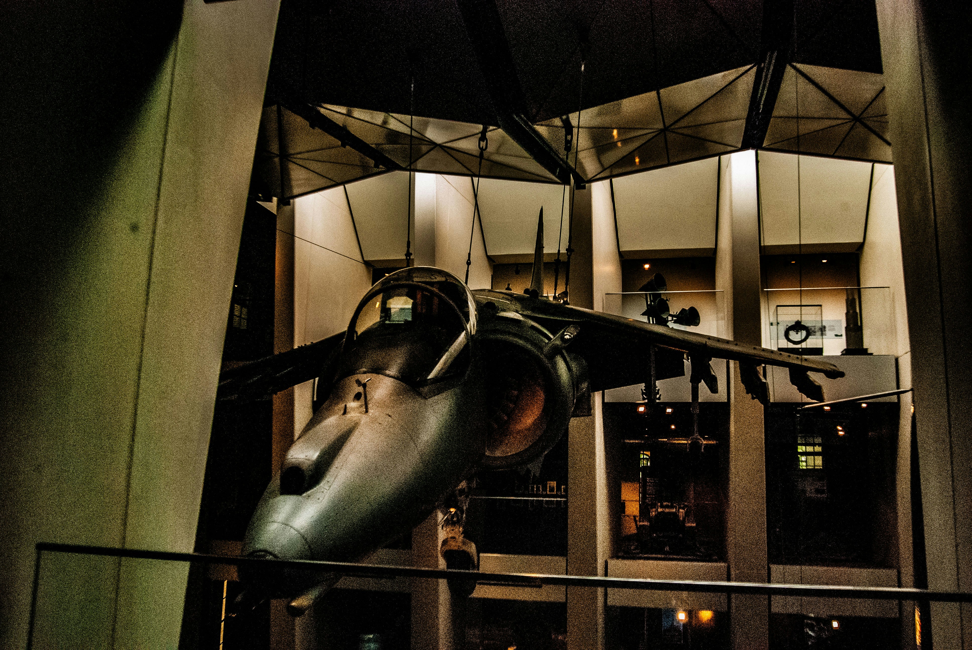 A fighter jet hangs suspended inside a modern building.