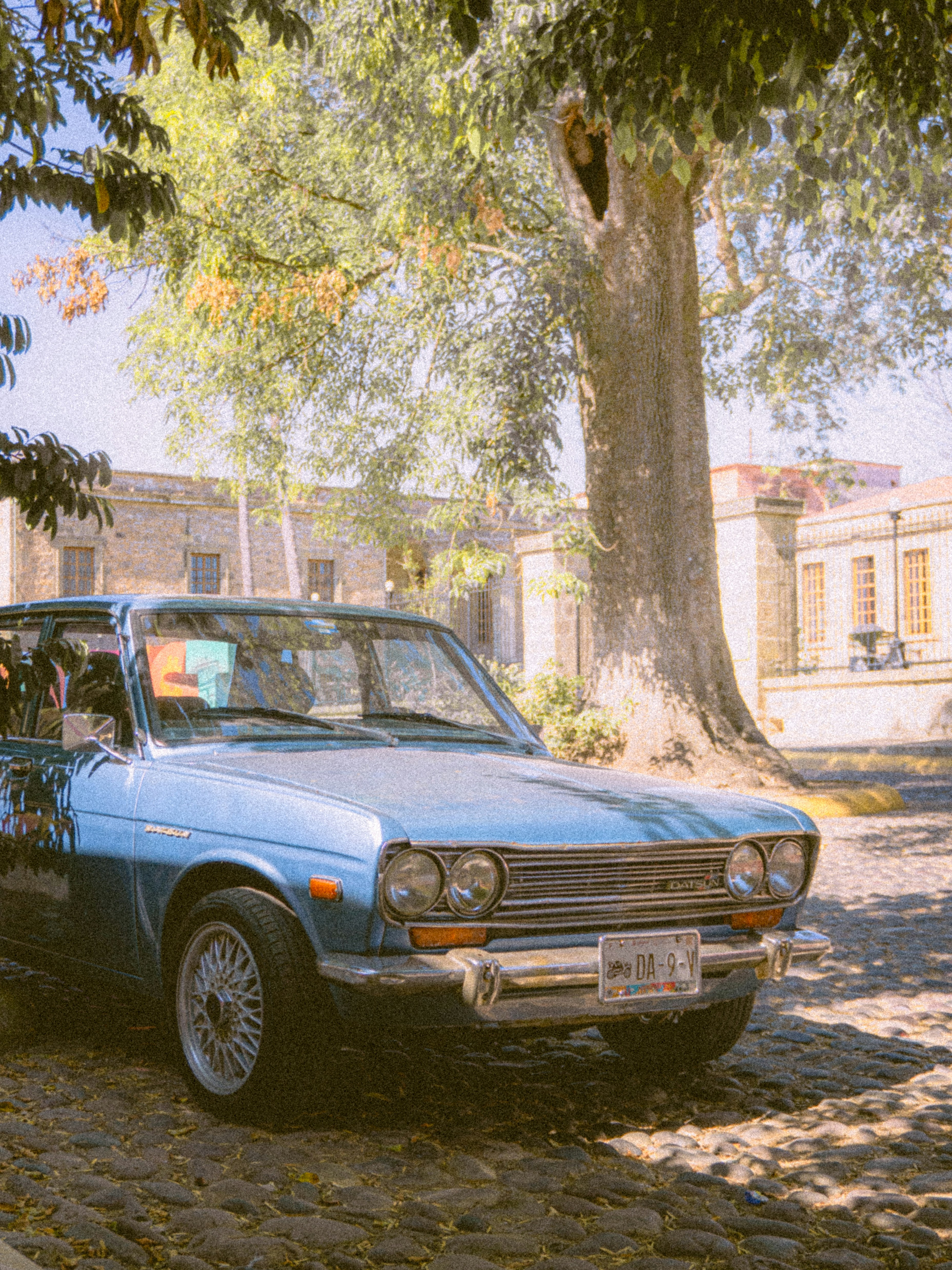 Vintage Blue Sedan under a Shaded Canopy
