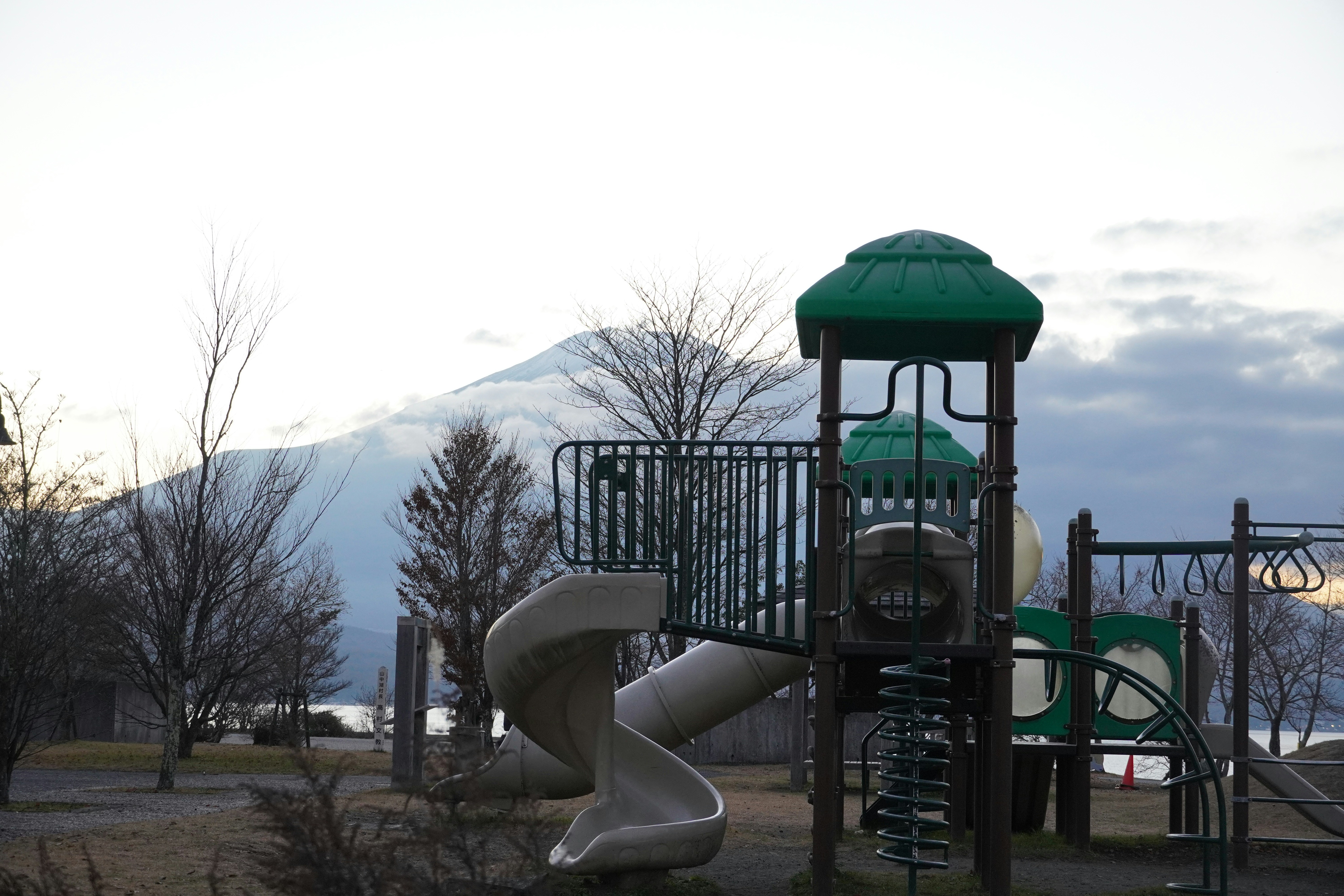 Snow-kissed hilltop playground under a quiet late-afternoon sky
