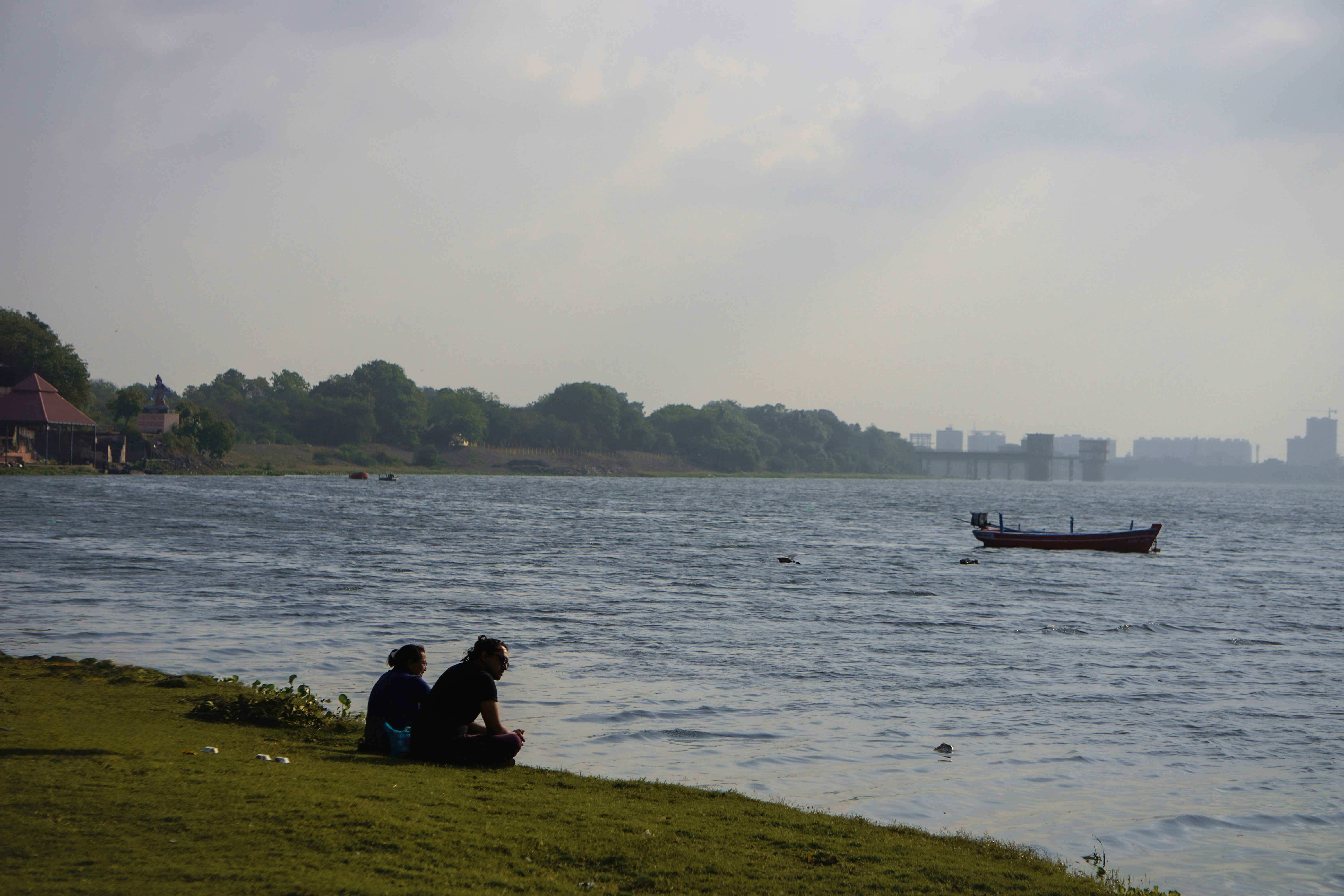 Quiet Shorelines: Friends by the Water with a Distant Boat