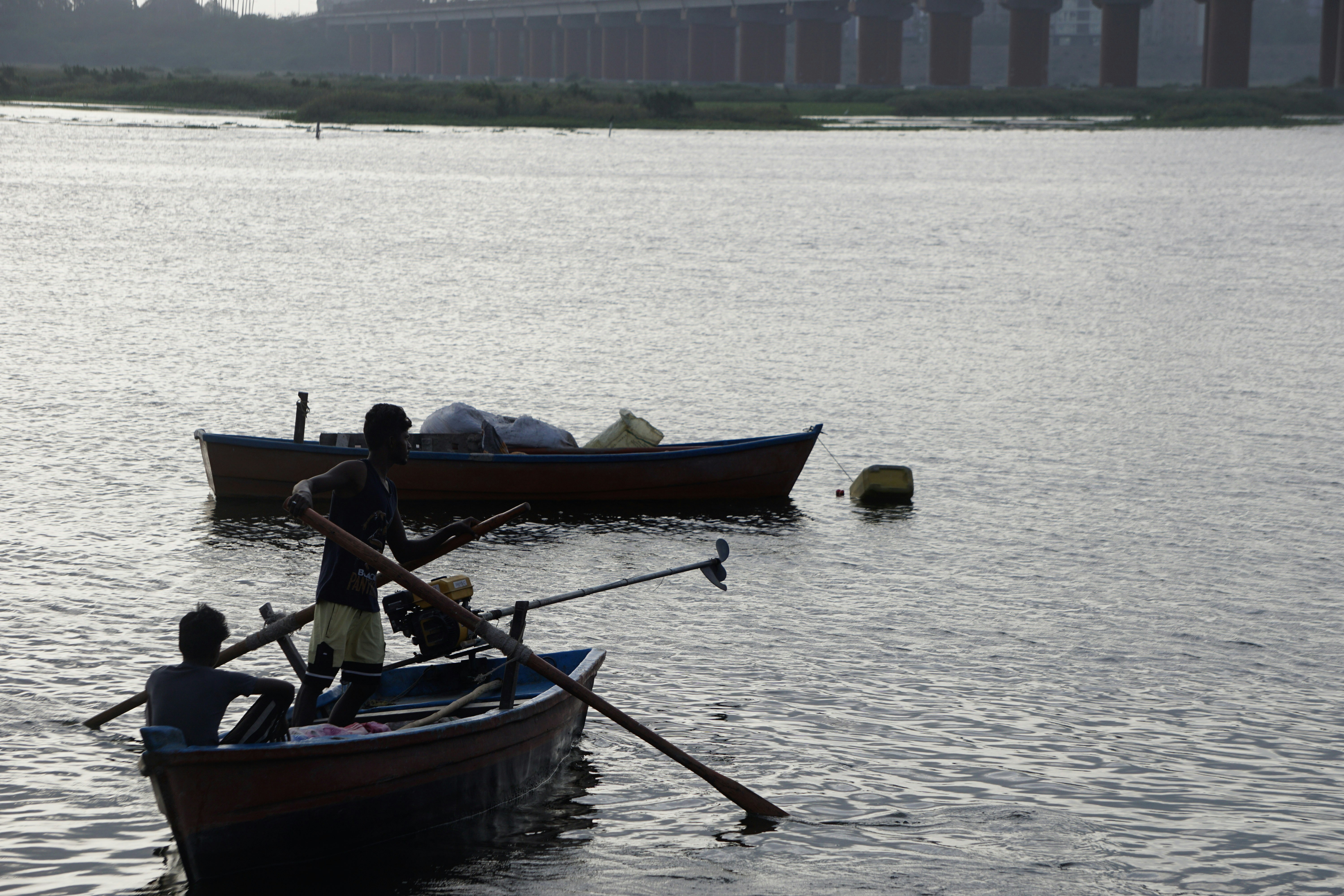Paddlers in silhouette Against a Distant Riverbank