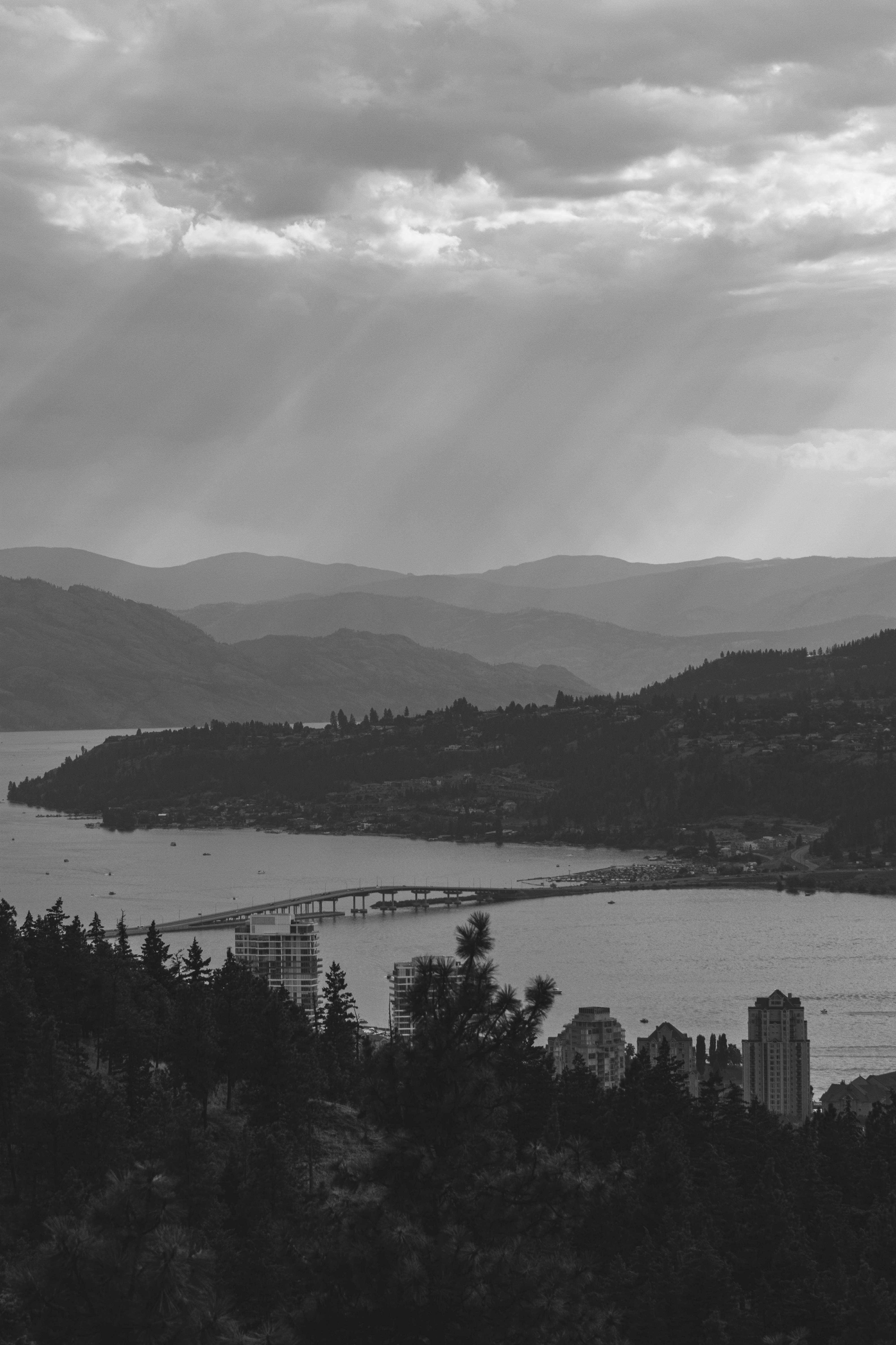 Shadowed Fjord: A Monochrome Panorama of Hills, Water, and Distant Bridges