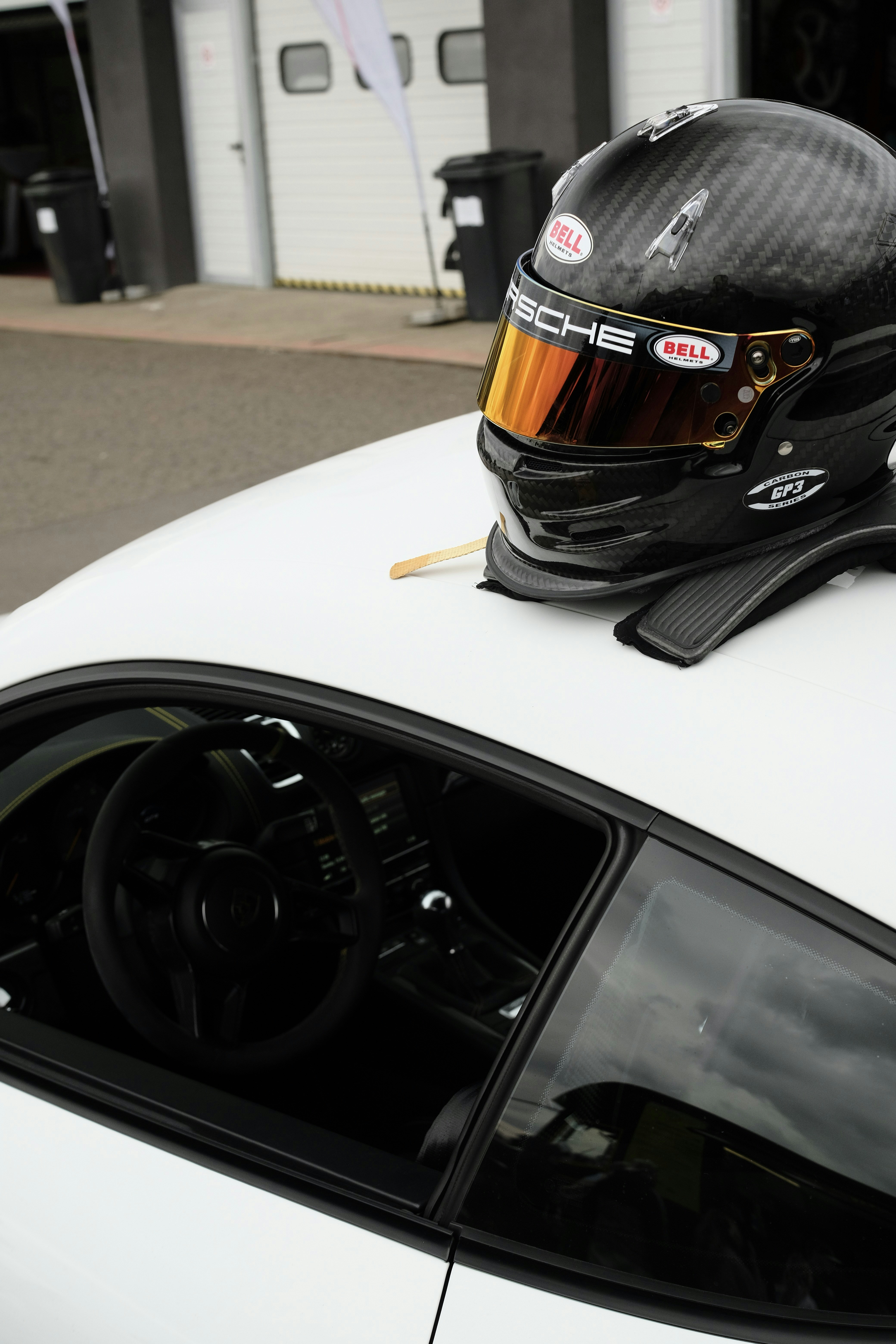 Racing Visage: Helmet Resting on a White Car Roof