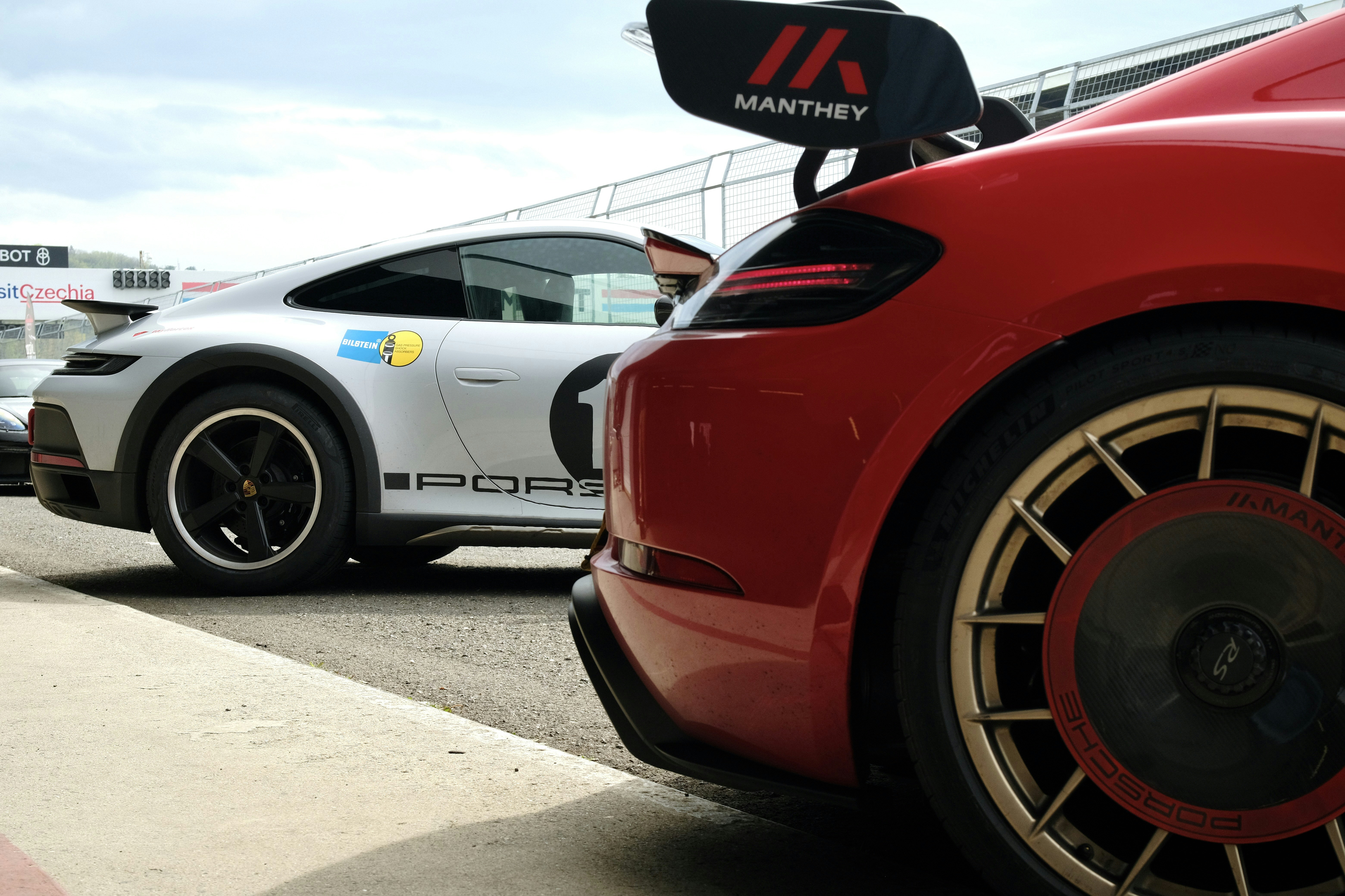 Two Racing Icons: RedItalian Core and White Porsche sit at the Track