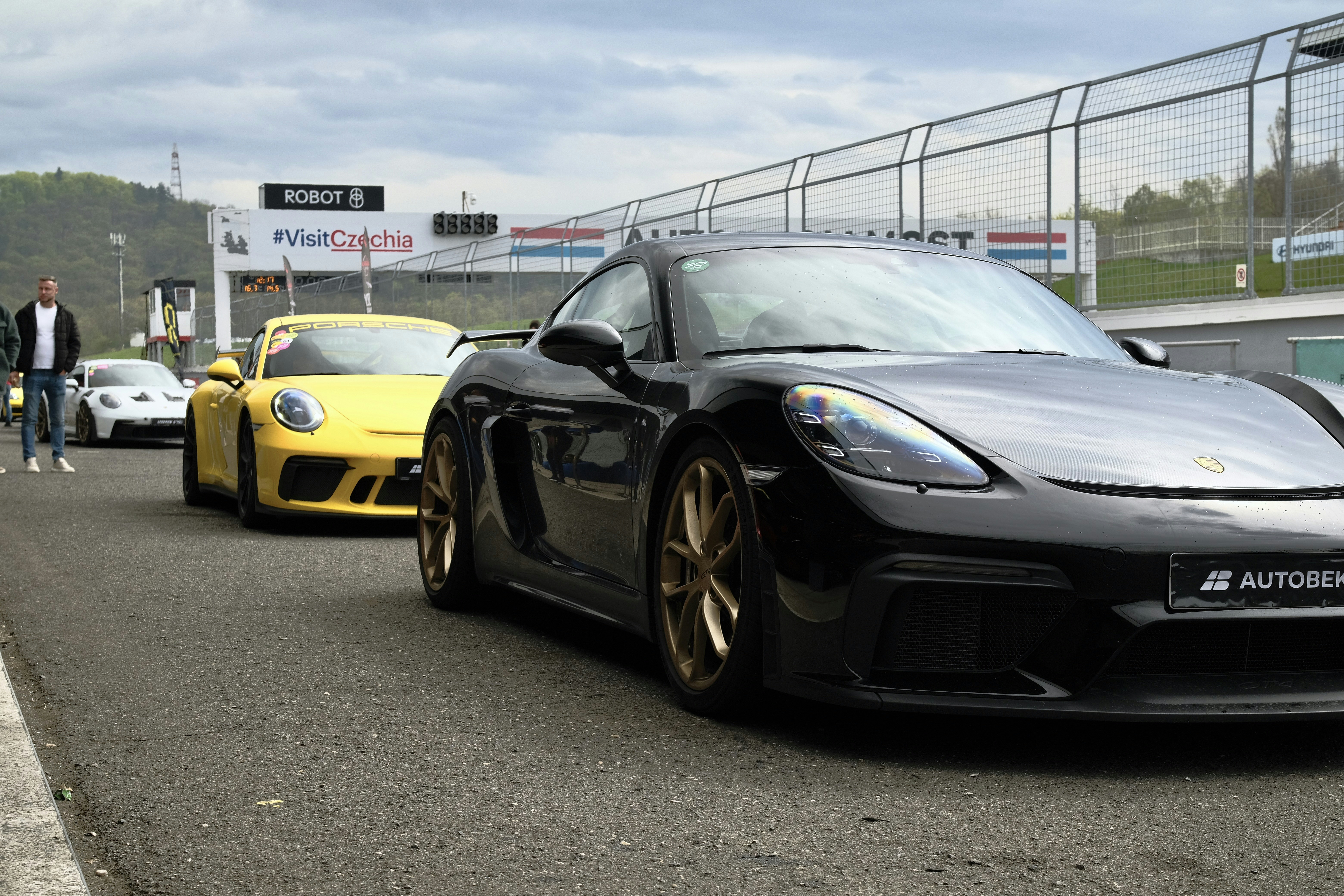 Black Porsche leads a line of sportscar racers down the pit lane