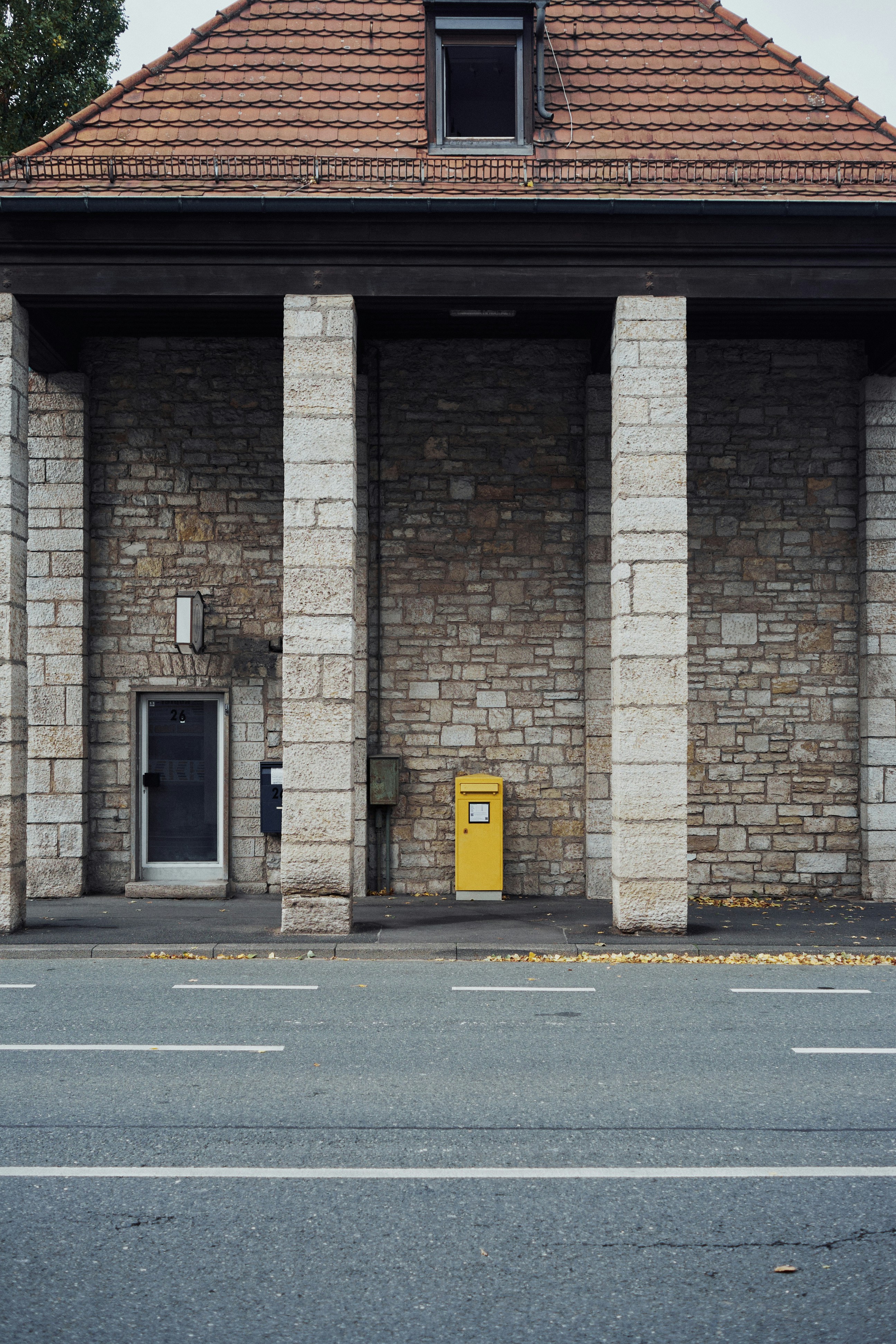 Stone Facade with Bright Yellow Mailbox under a Hushed Archway