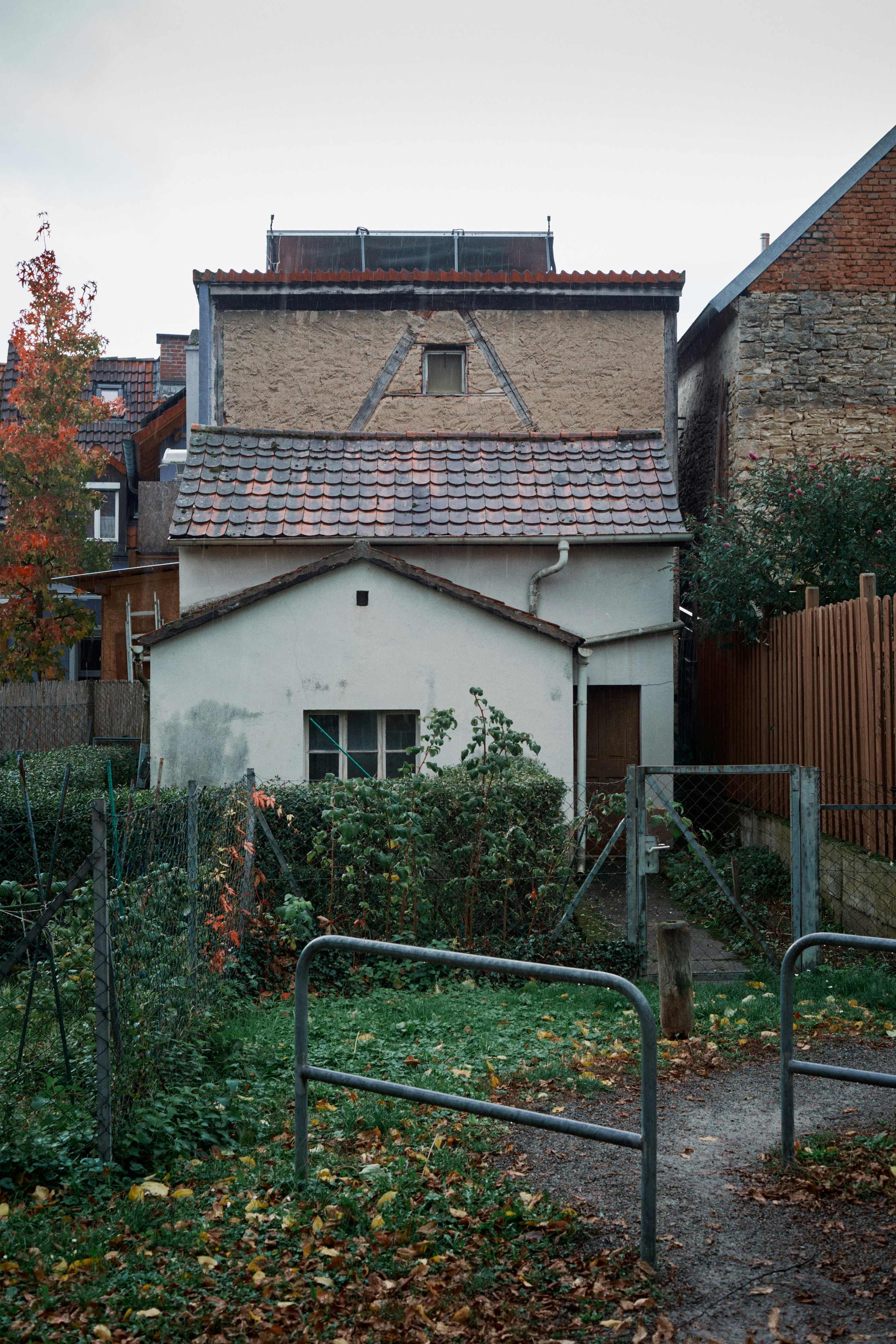 Quiet Urban Oasis: A Weathered House Nestled Behind Fenced Garden