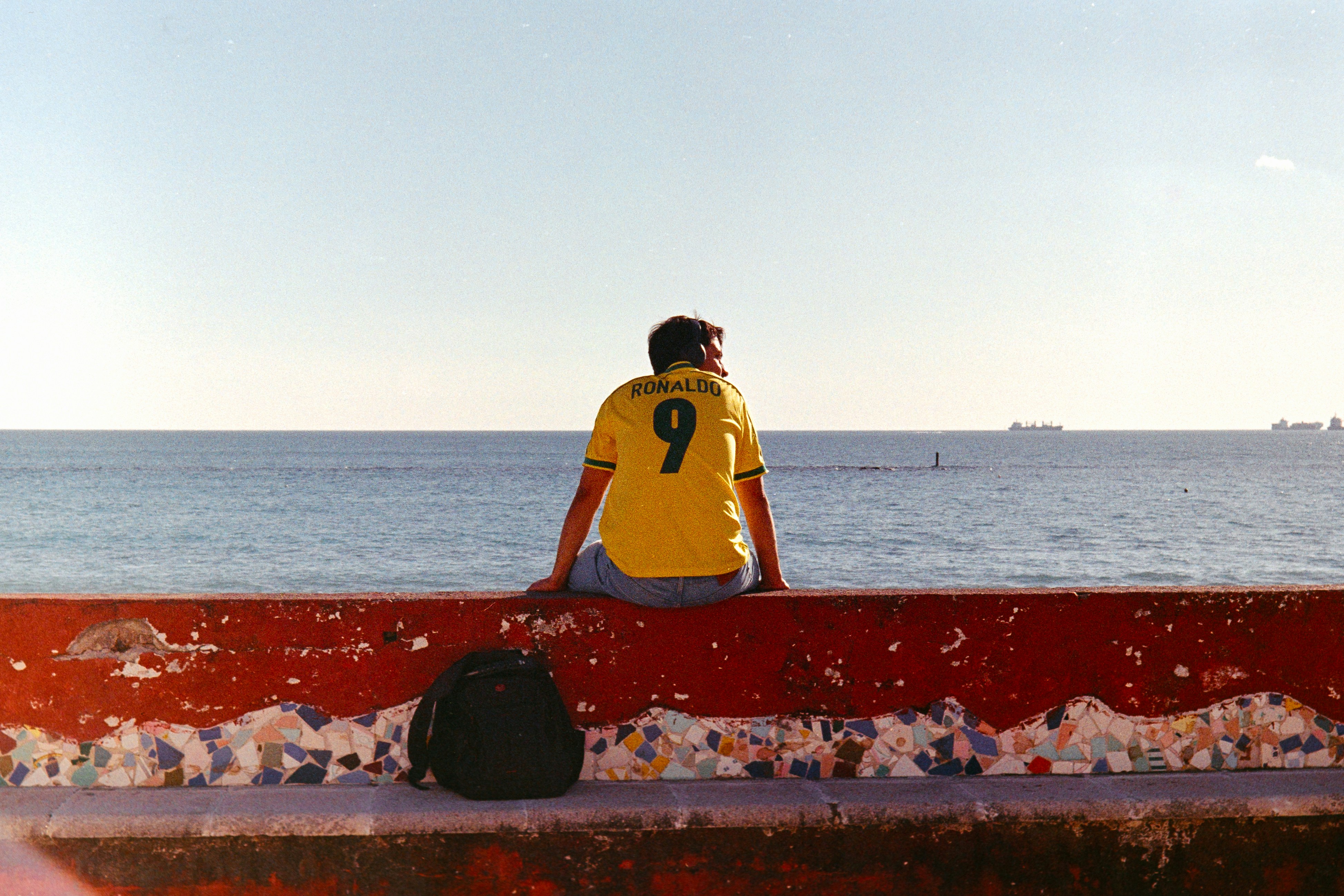 Seated by the Sea: A Lone Fan in a Yellow Jersey Gazes Toward the Horizon
