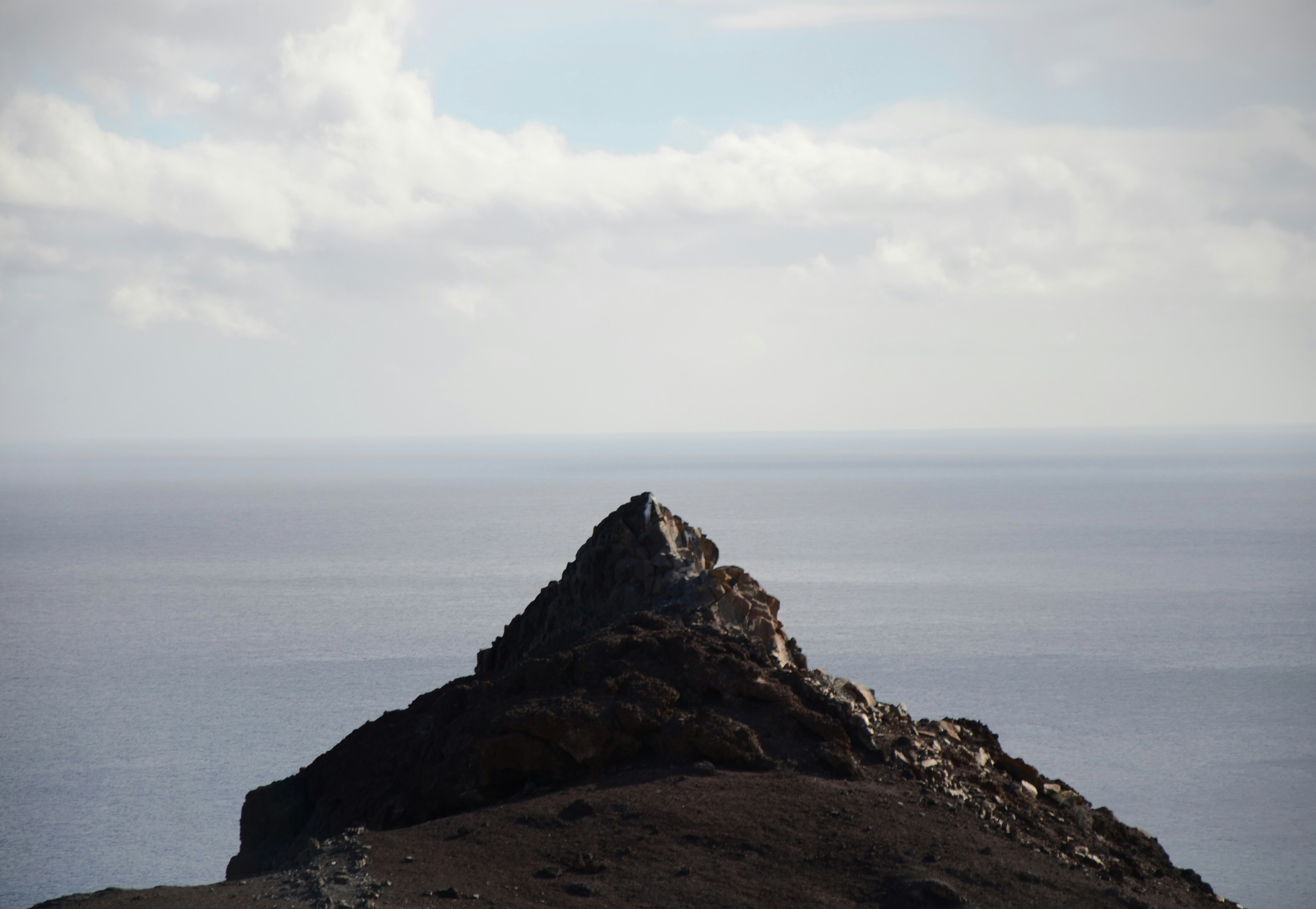 Rugged Prominence: A Lone Peak Against the Sea Horizon