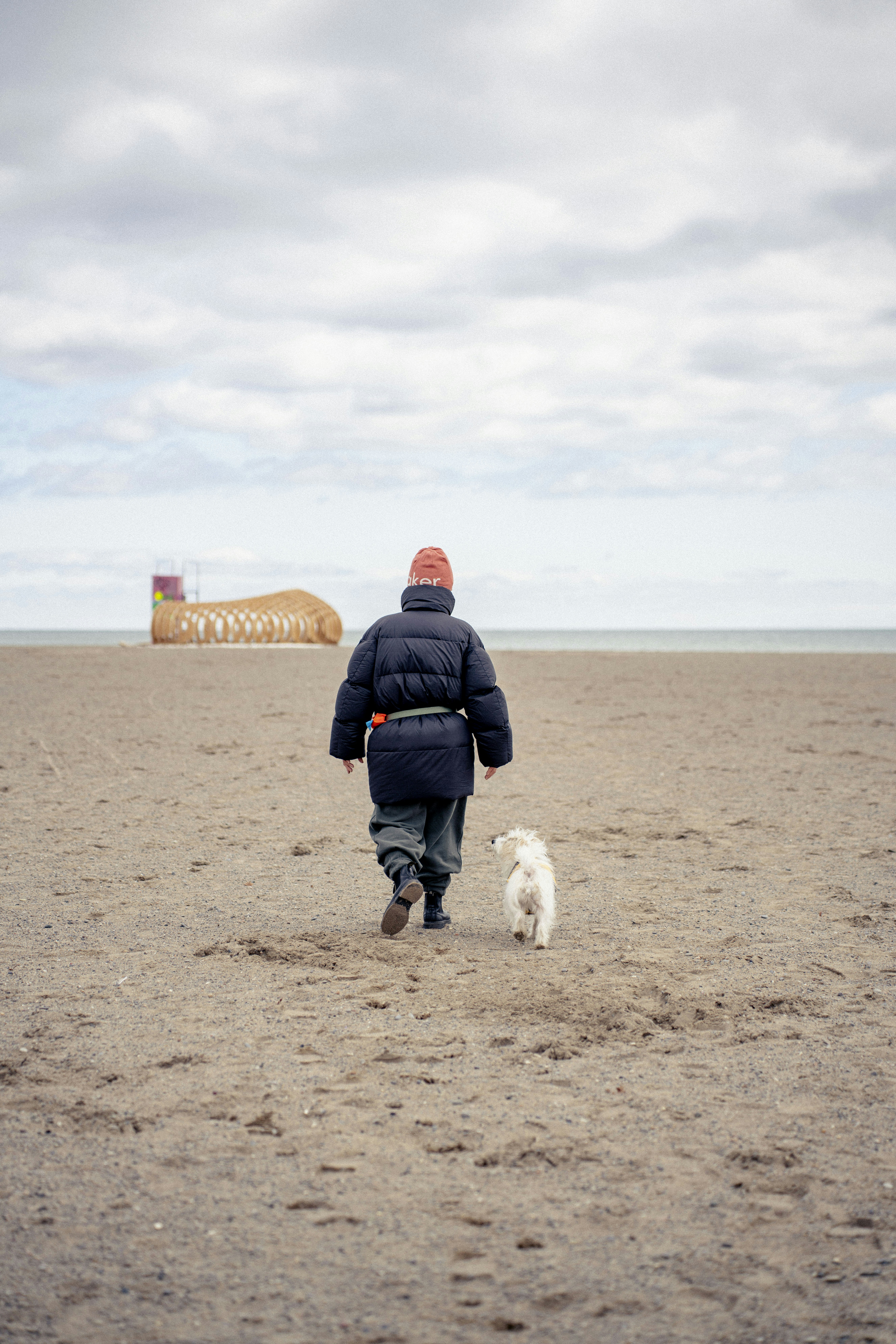 Two Figures, One Path: A Child and a Dog Trek Across a Quiet Seaside