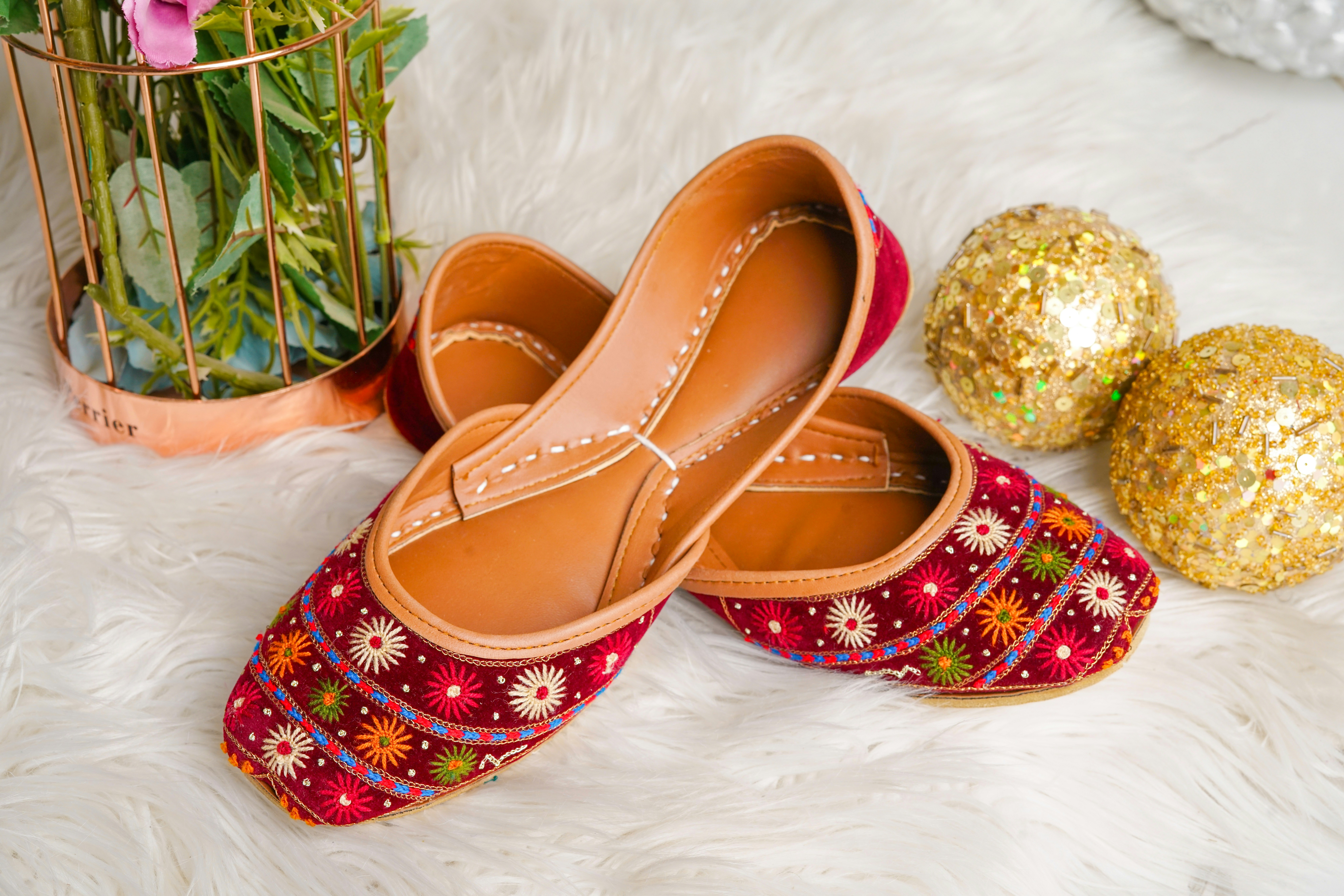 Embroidered flats resting on a plush backdrop with festive gold orbs