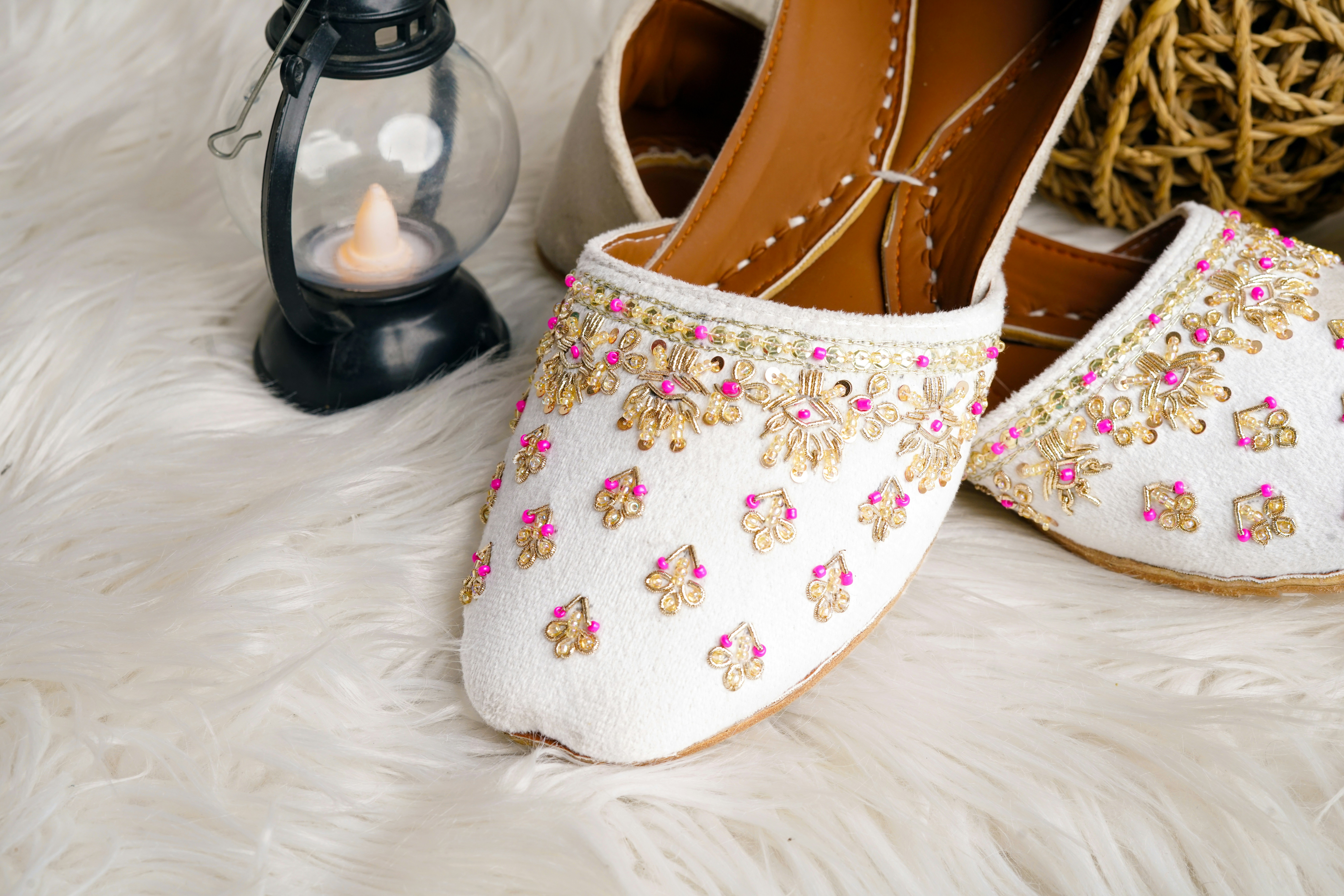 Embroidered bridal flats resting beside a candle