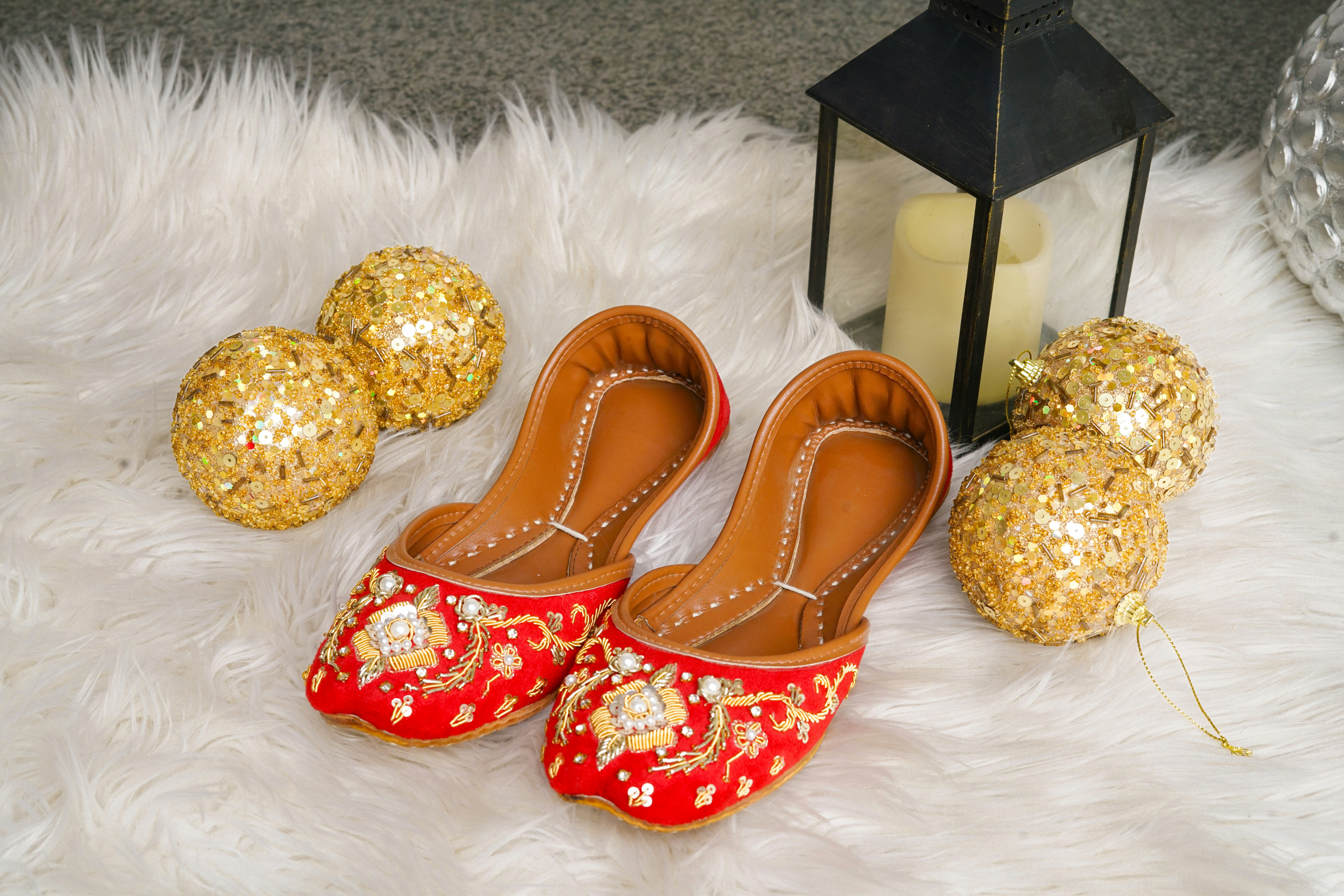 Red embellished slippers resting beside a glow of gold orbs and a lantern