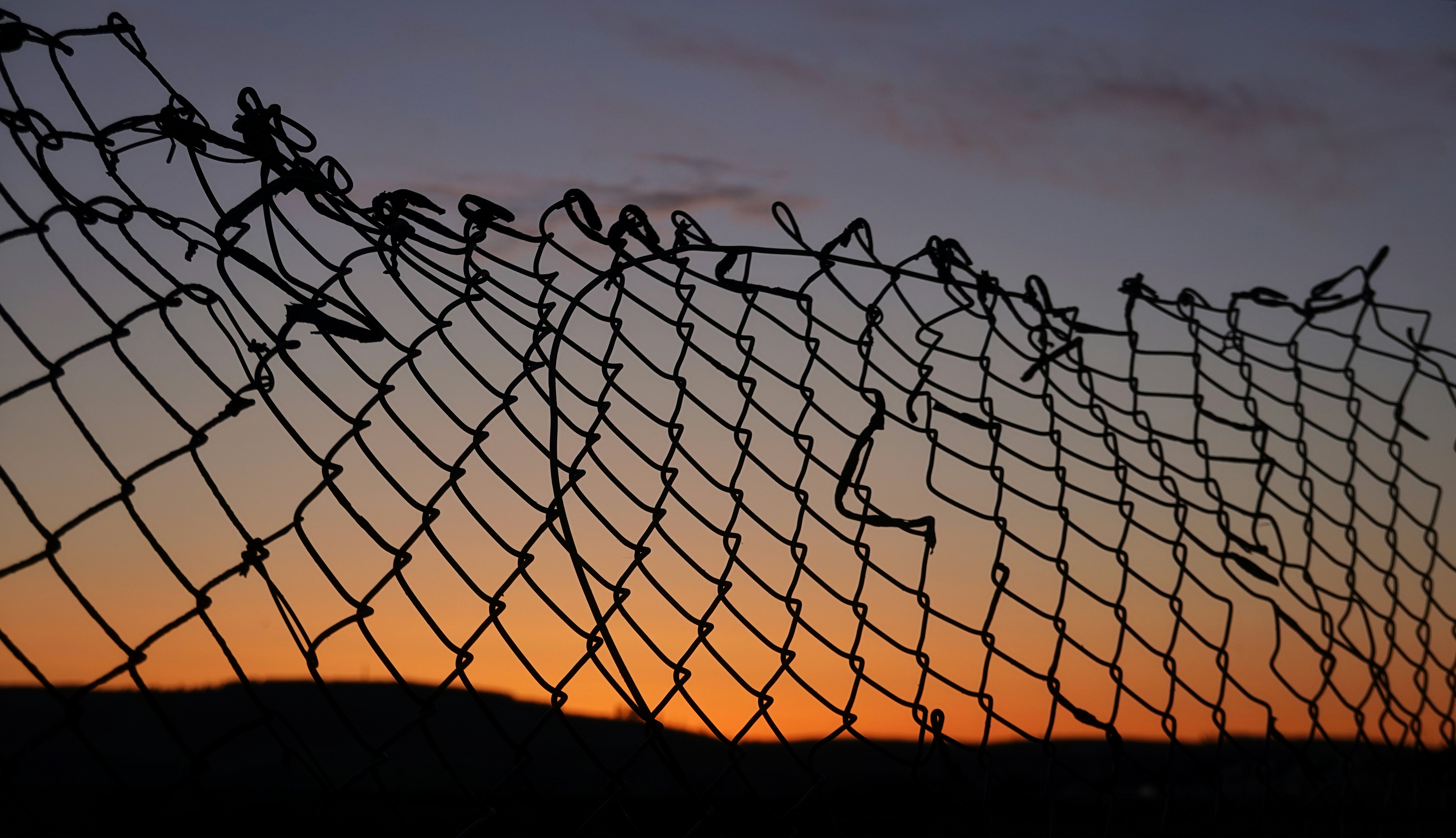 Sunset Veil: A Curved Chain-Link Silhouette against a Quiet Horizon