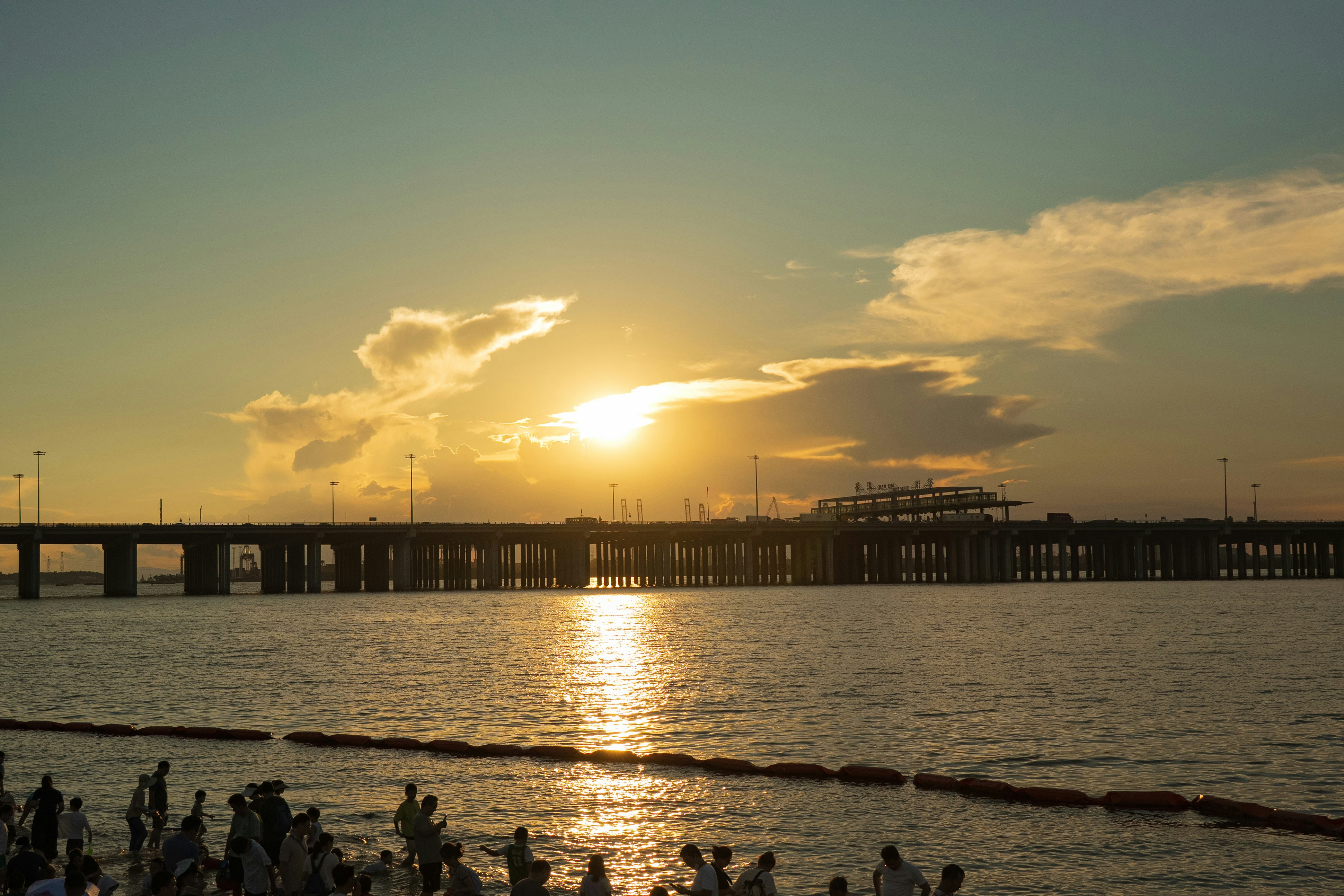 Sunlit Pier at Dusk: People and Skyline in Golden Hour