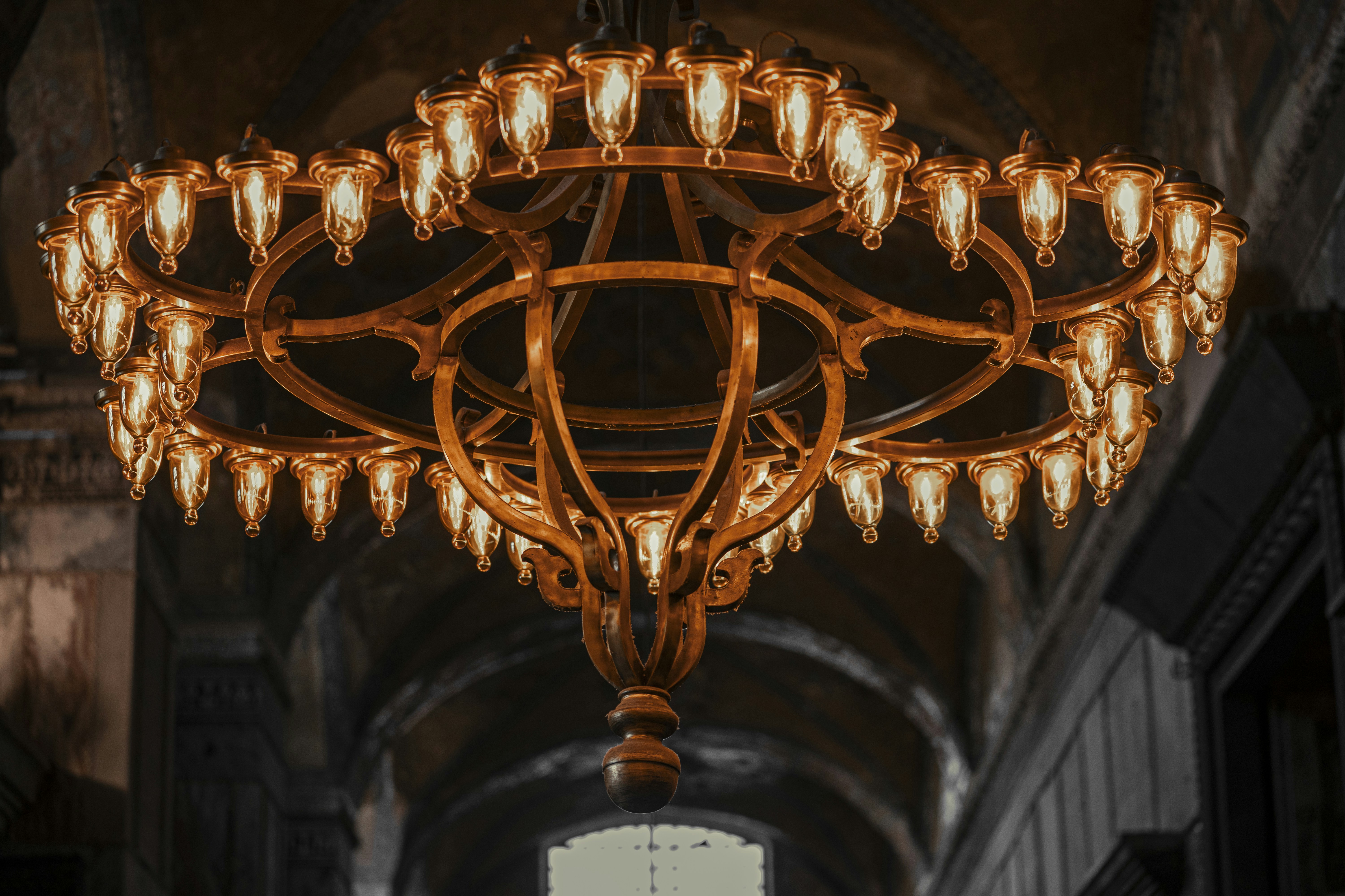 Golden Orbit: An Antique Chandelier Illuminates a Dim Corridor