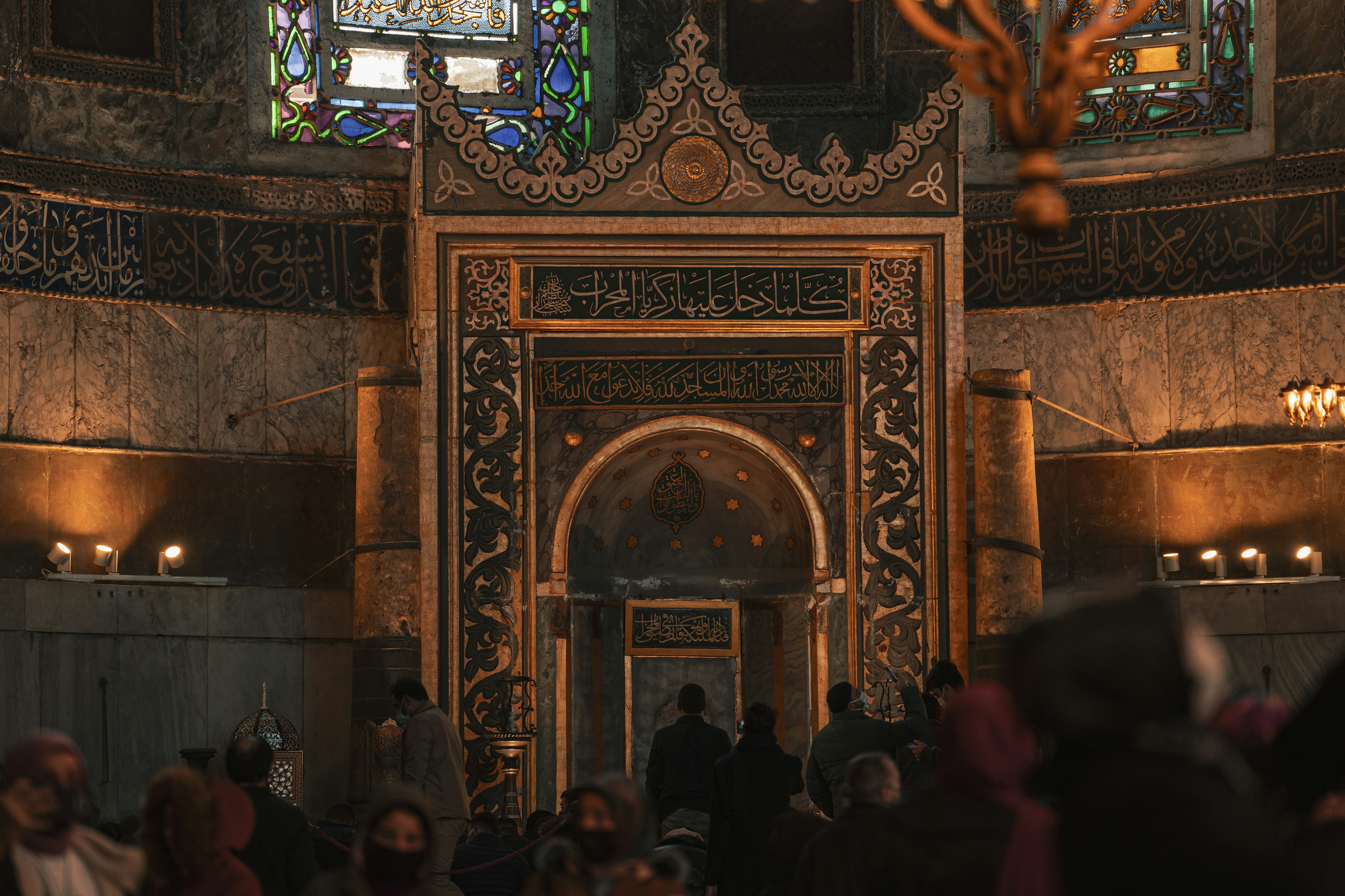 Golden Archway Framed by Worshippers in an Ornate Mosque Hall