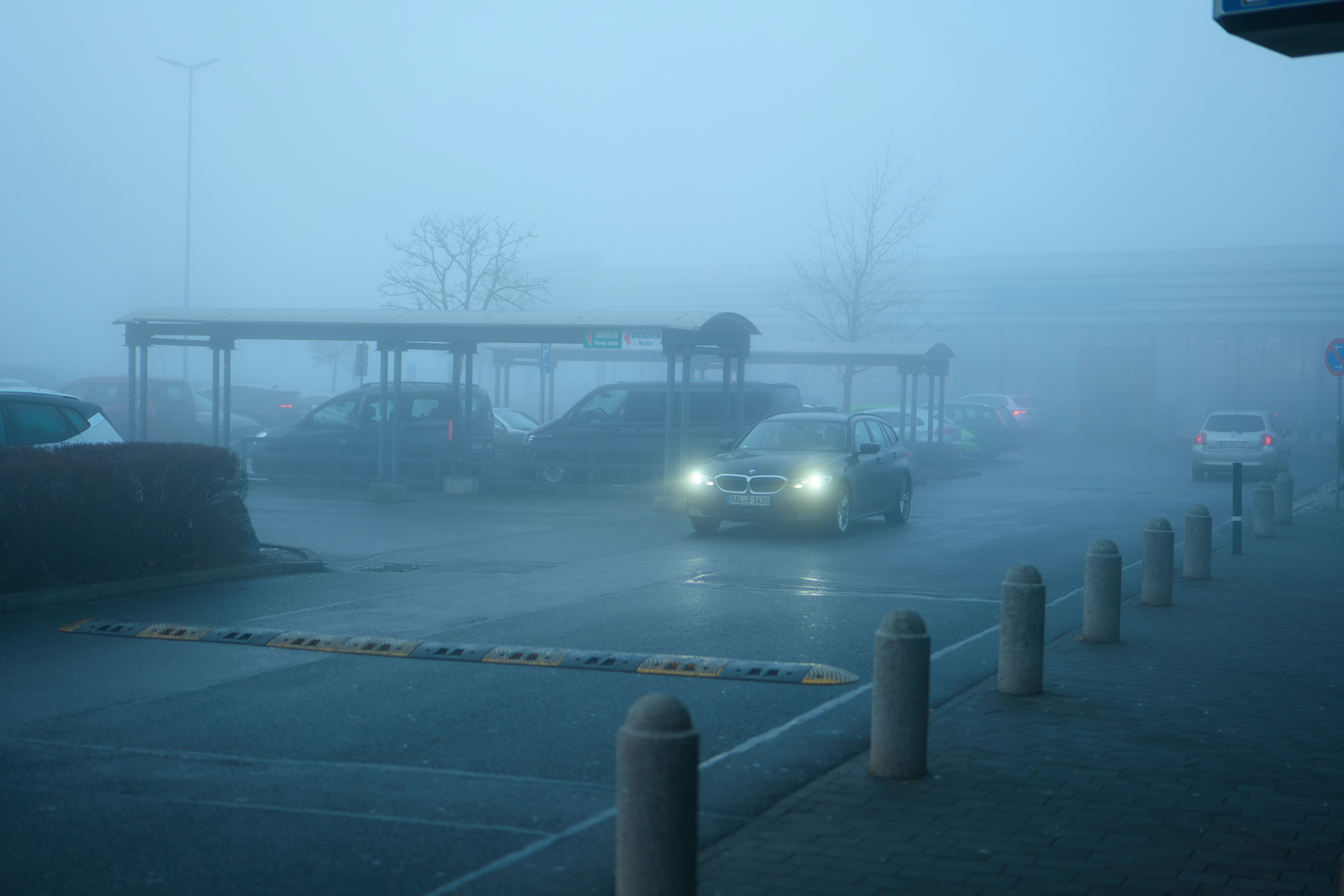 Headlights Through the Mist: A Quiet Car Courtyard in Dense Fog
