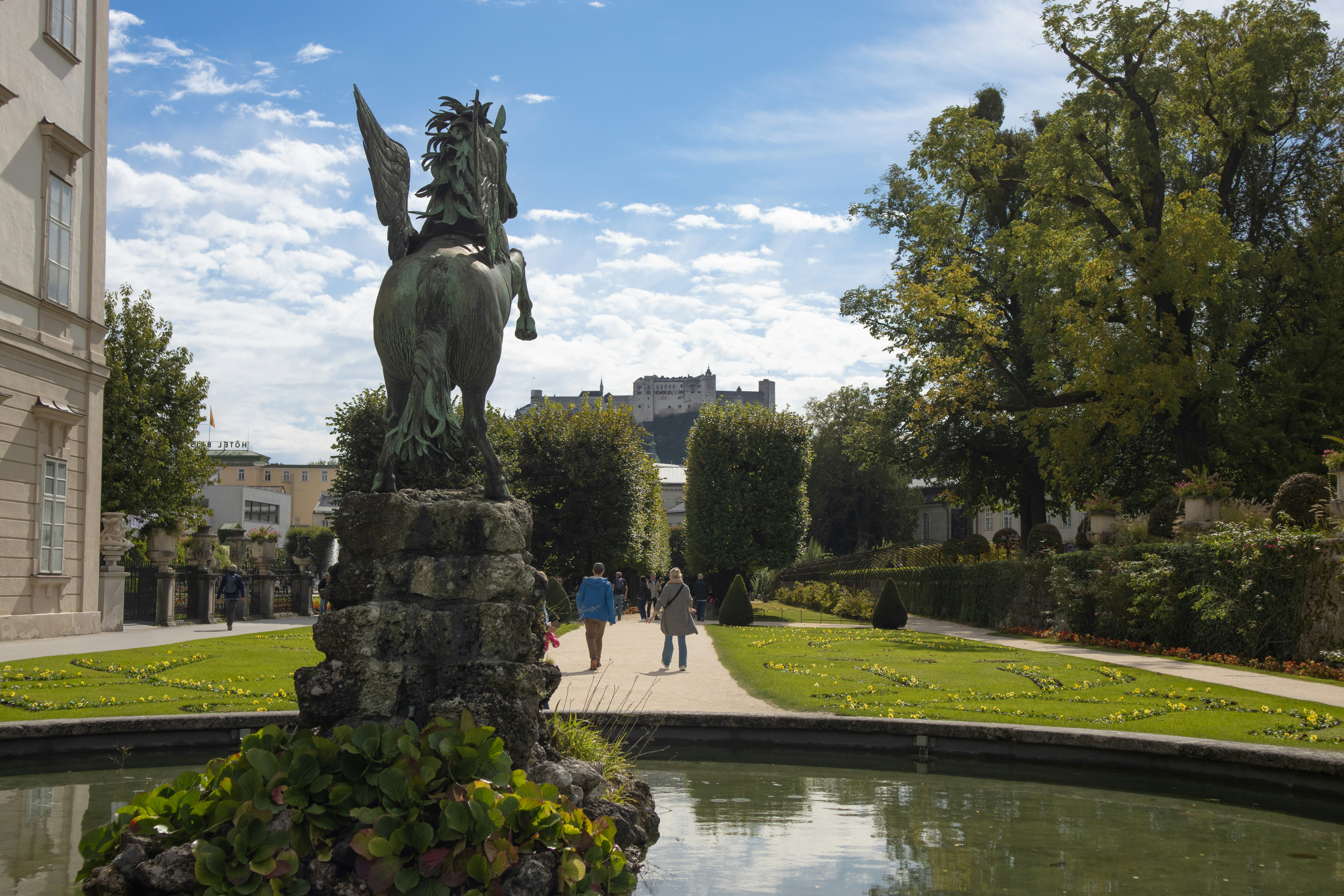  statue on a pedestal overlooking a sunlit parklike avenue