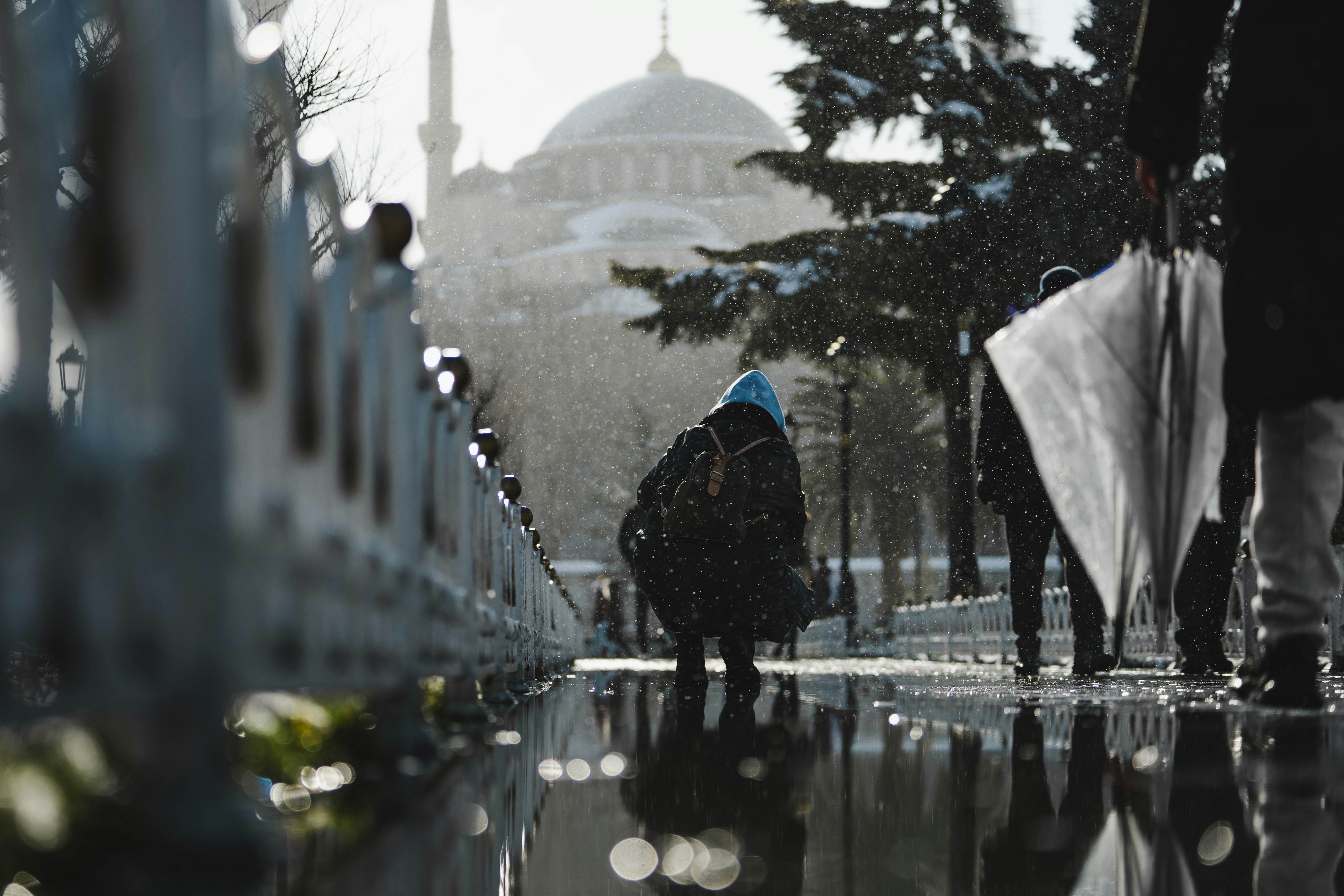 Blue-Hooded Figure in a Slushy Path Under Snowfall