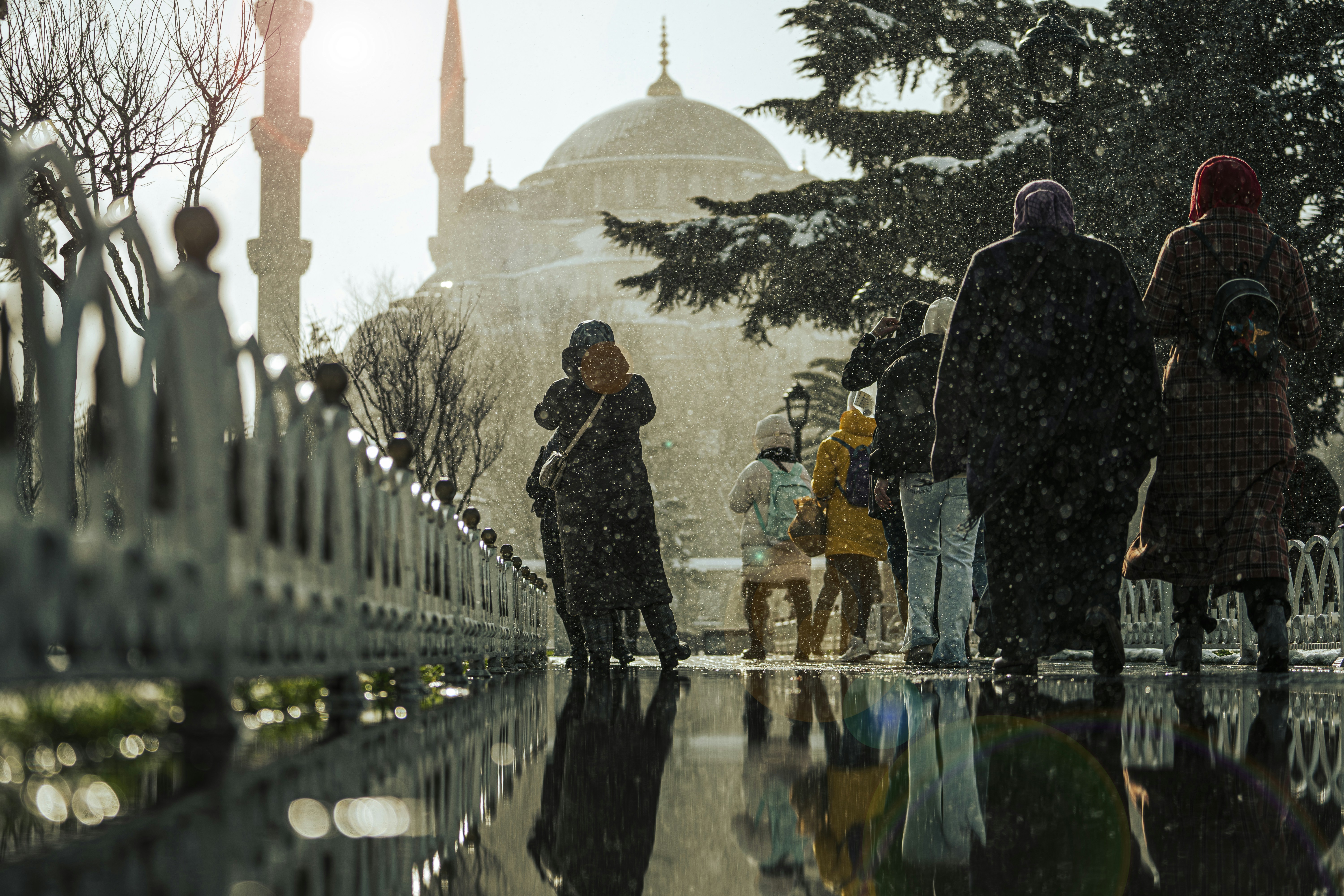 Crowds against a grand domed backdrop: winter rain at the mosque