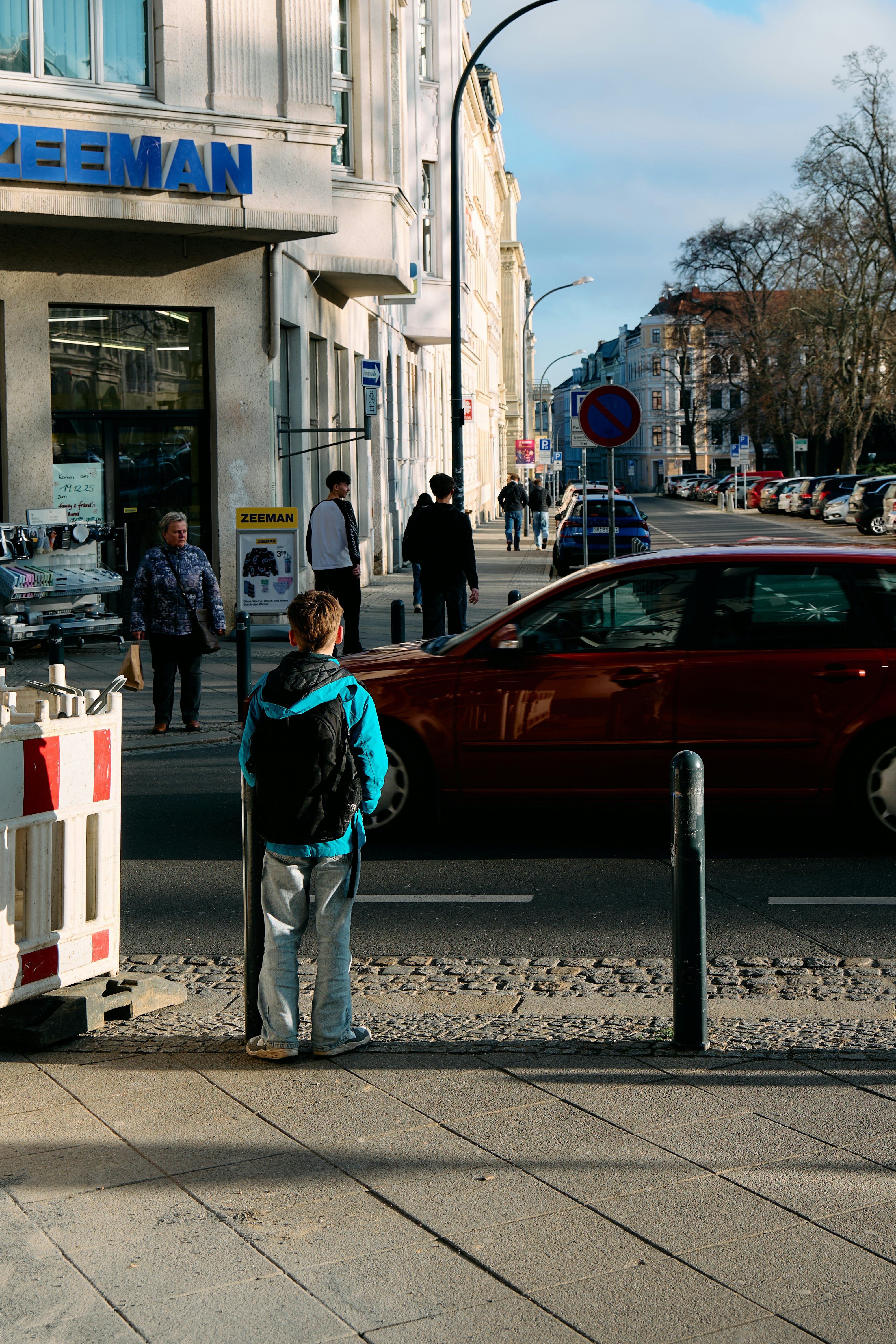 Street Scene at Dusk: A Child with Blue Backpack Stops to Watch Traffic