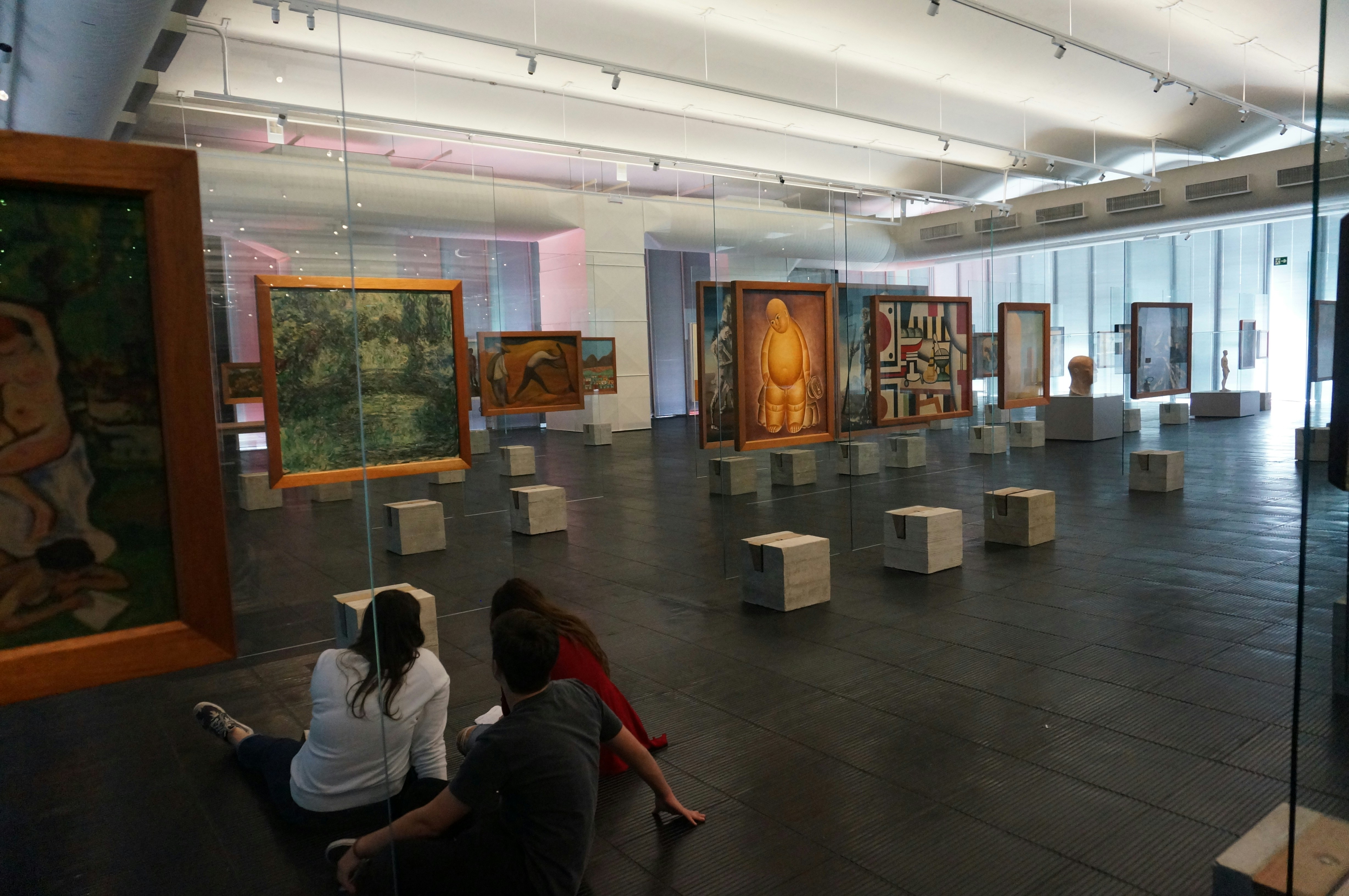 Gallery stillness: visitors rest near vibrant frames