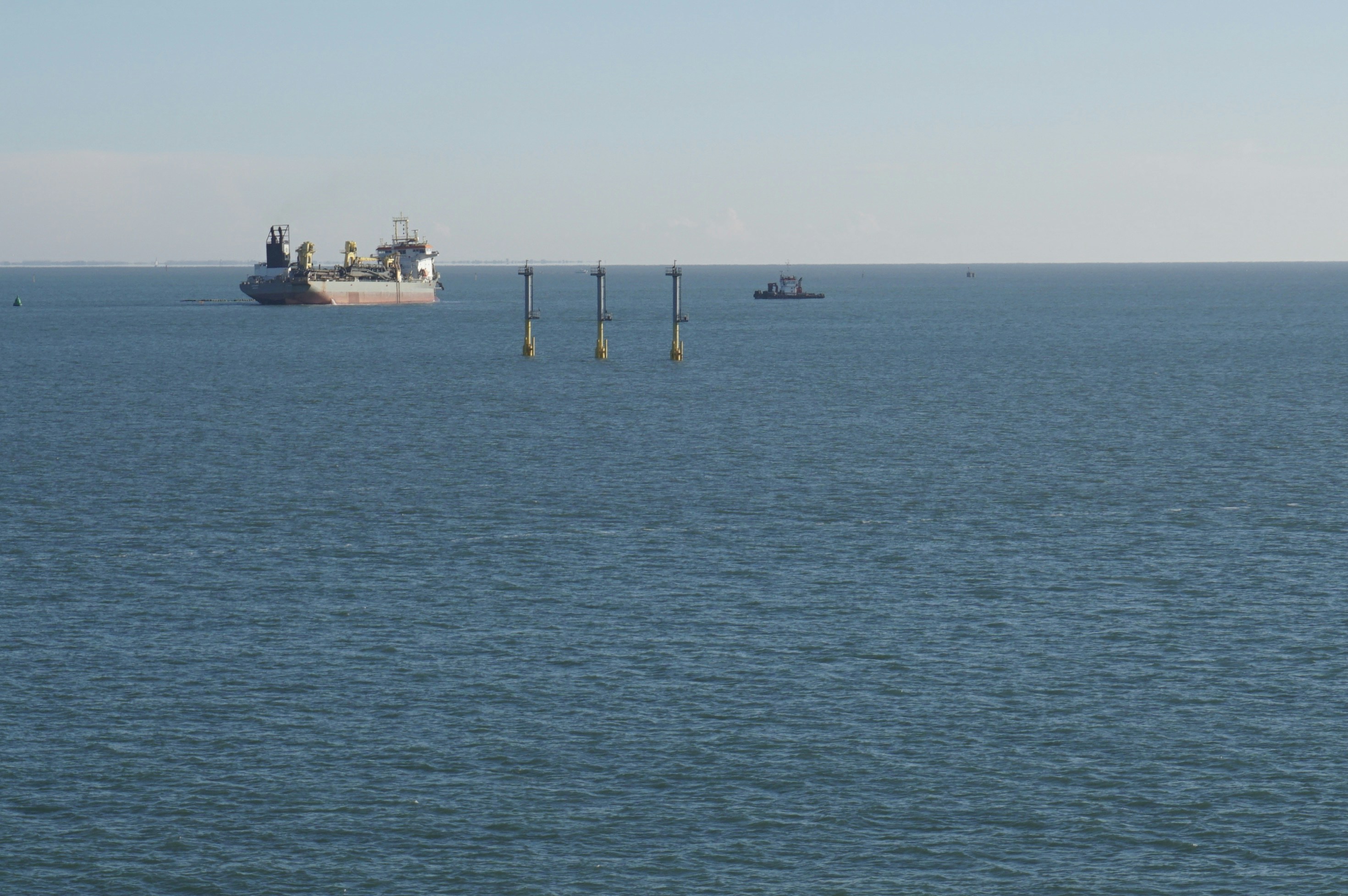 Two distant vessels and a line of pilings slicing the horizon